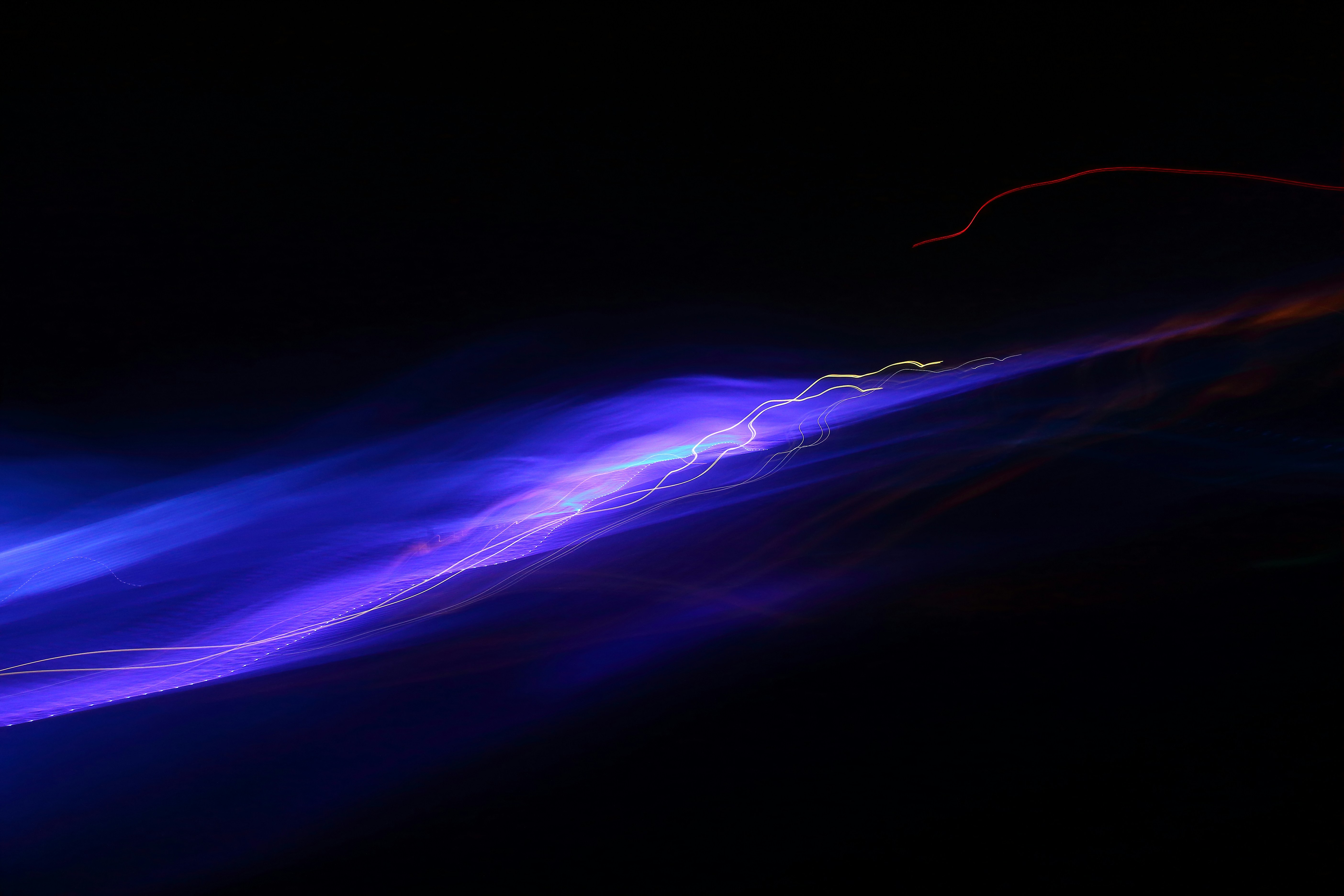 Abstract light trails in vibrant blue and purple hues against a dark background, suggesting motion and energy.