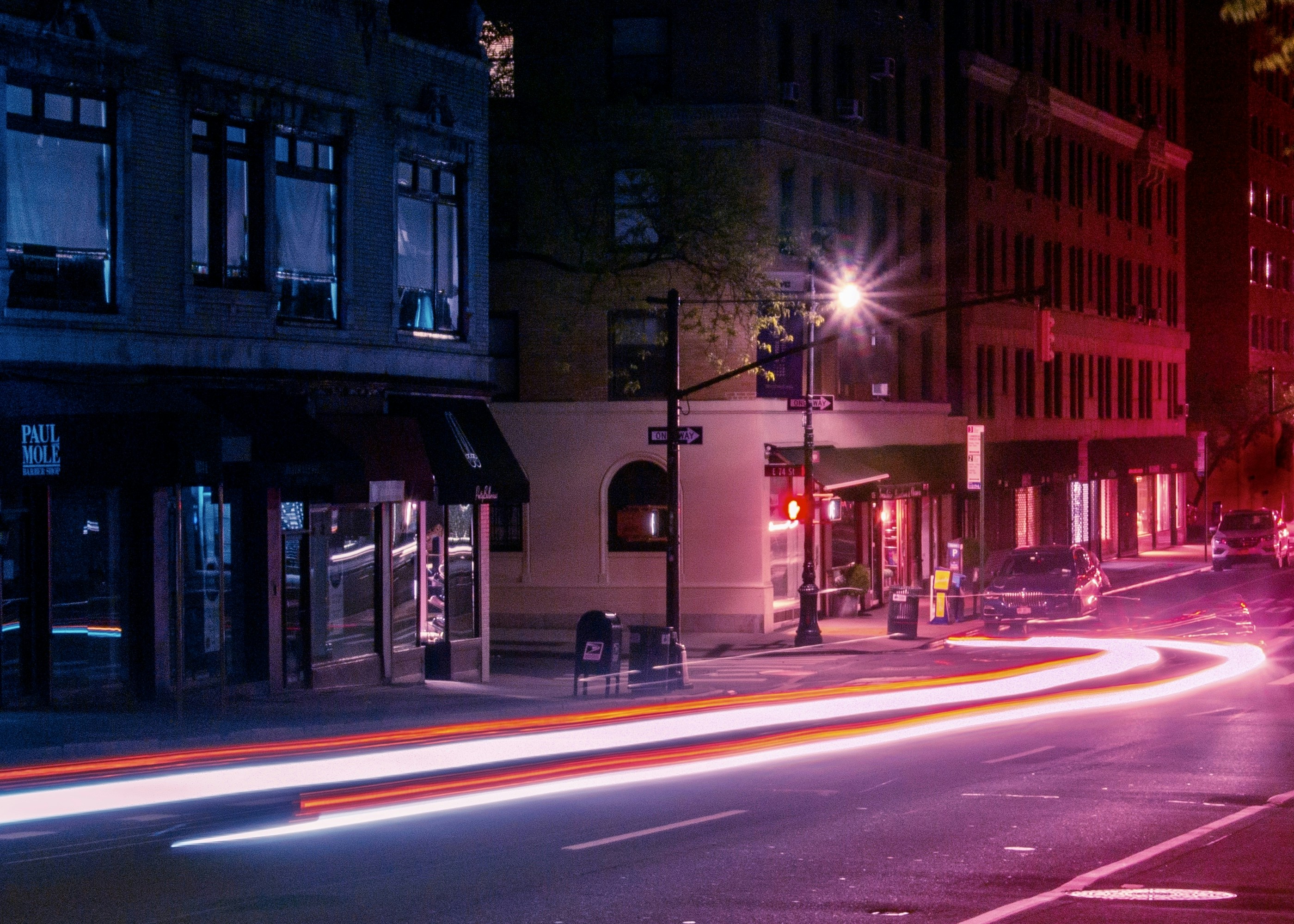 A vibrant urban scene showcasing light trails from passing cars against a backdrop of illuminated buildings at night.