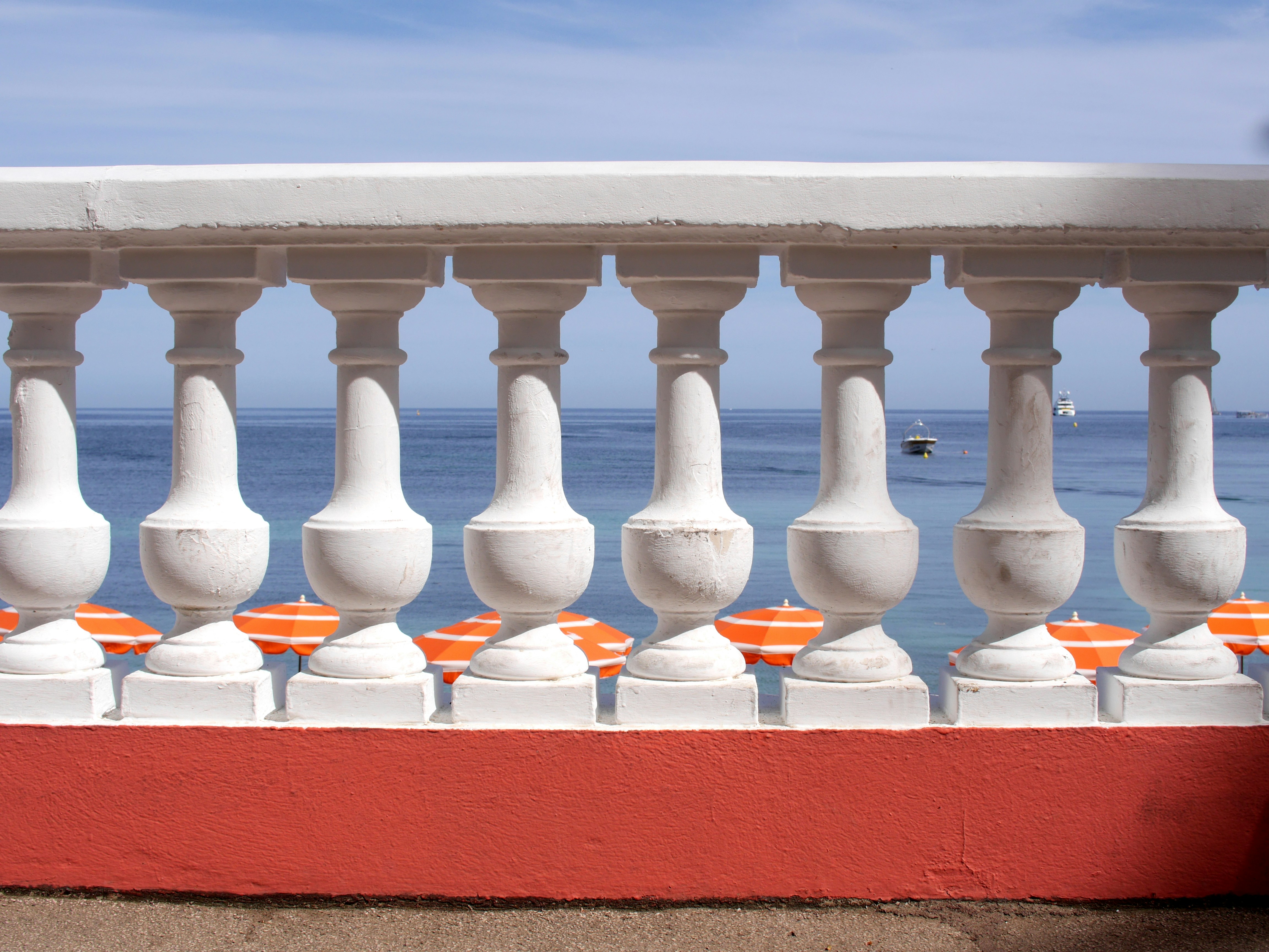 White balustrade overlooking the calm Mediterranean Sea under a clear blue sky.