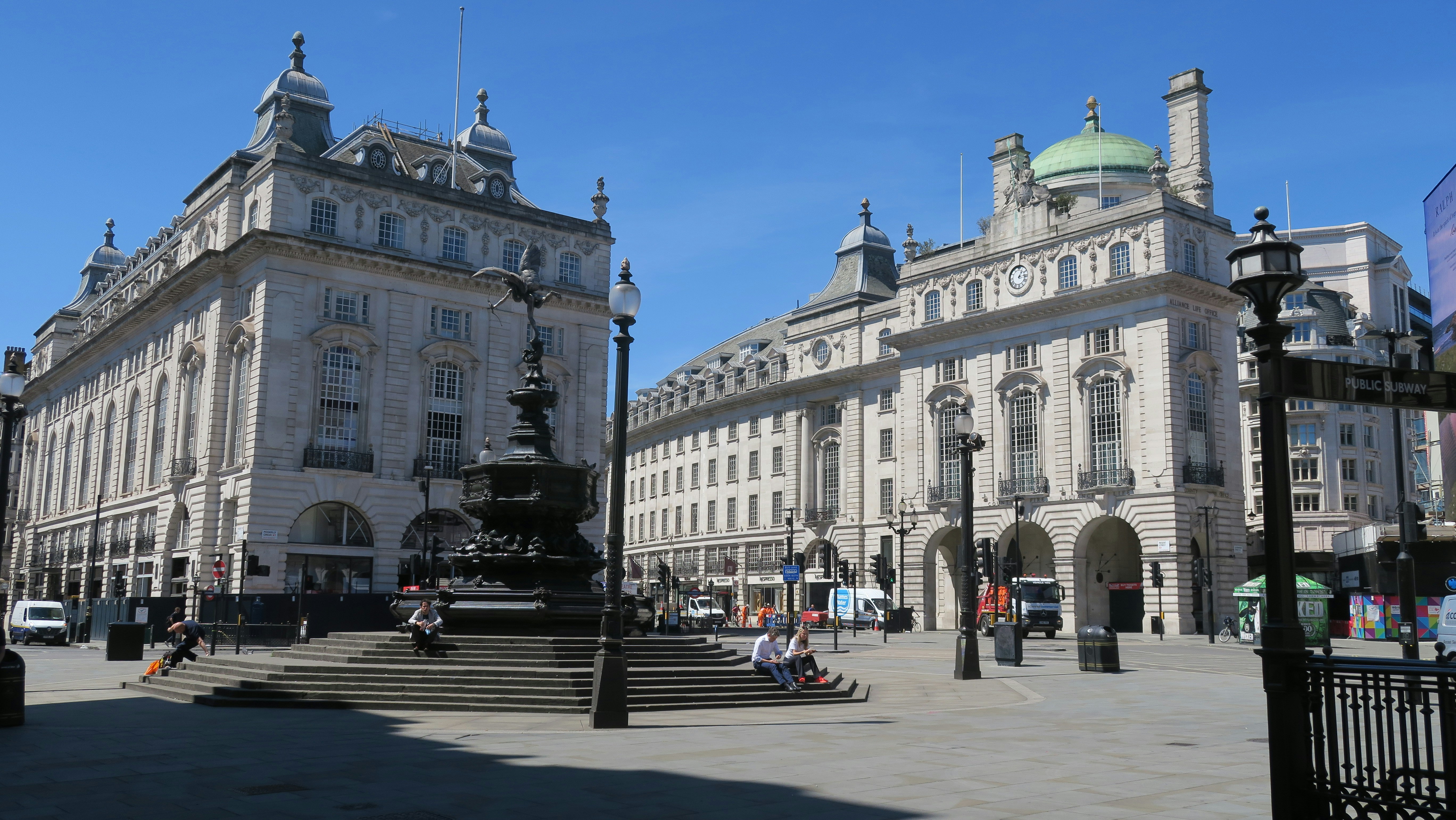 Historic buildings and fountain in Piccadilly Circus under a clear blue sky.
