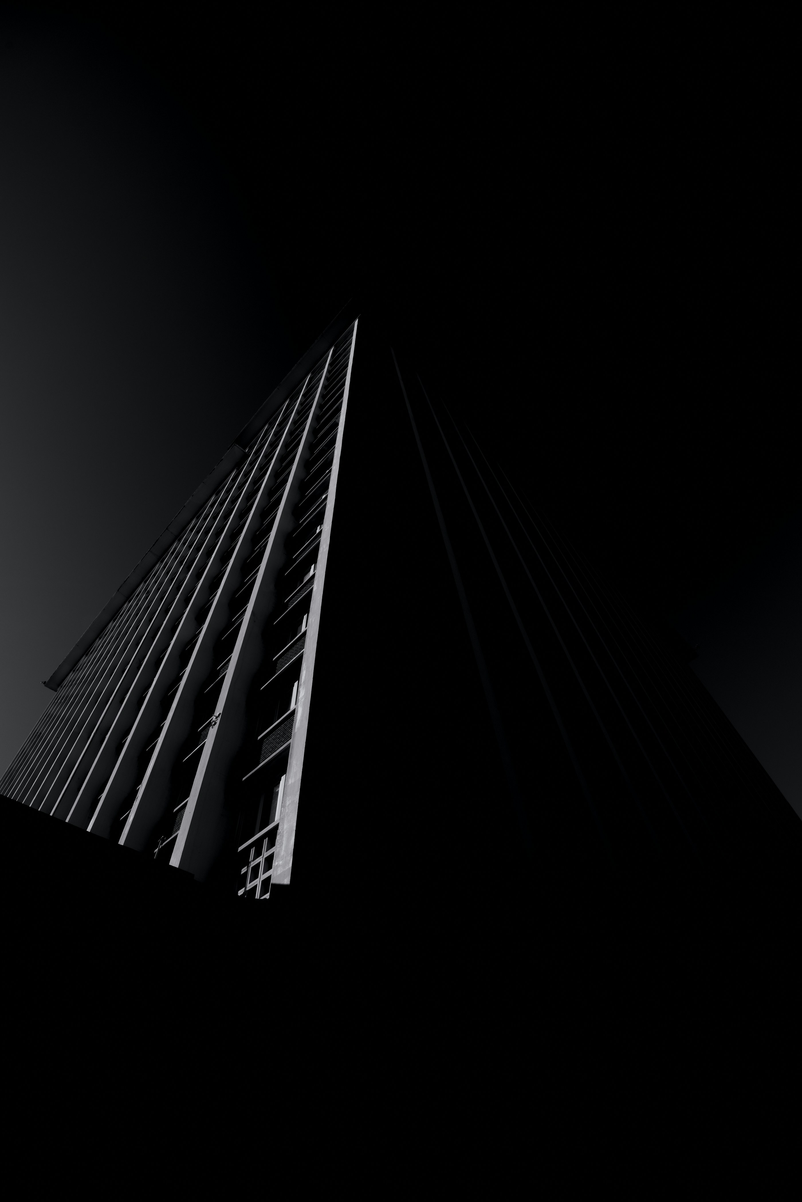 High-rise building captured from a low angle, showcasing its angular lines and contrasting shadows against a dark backdrop.
