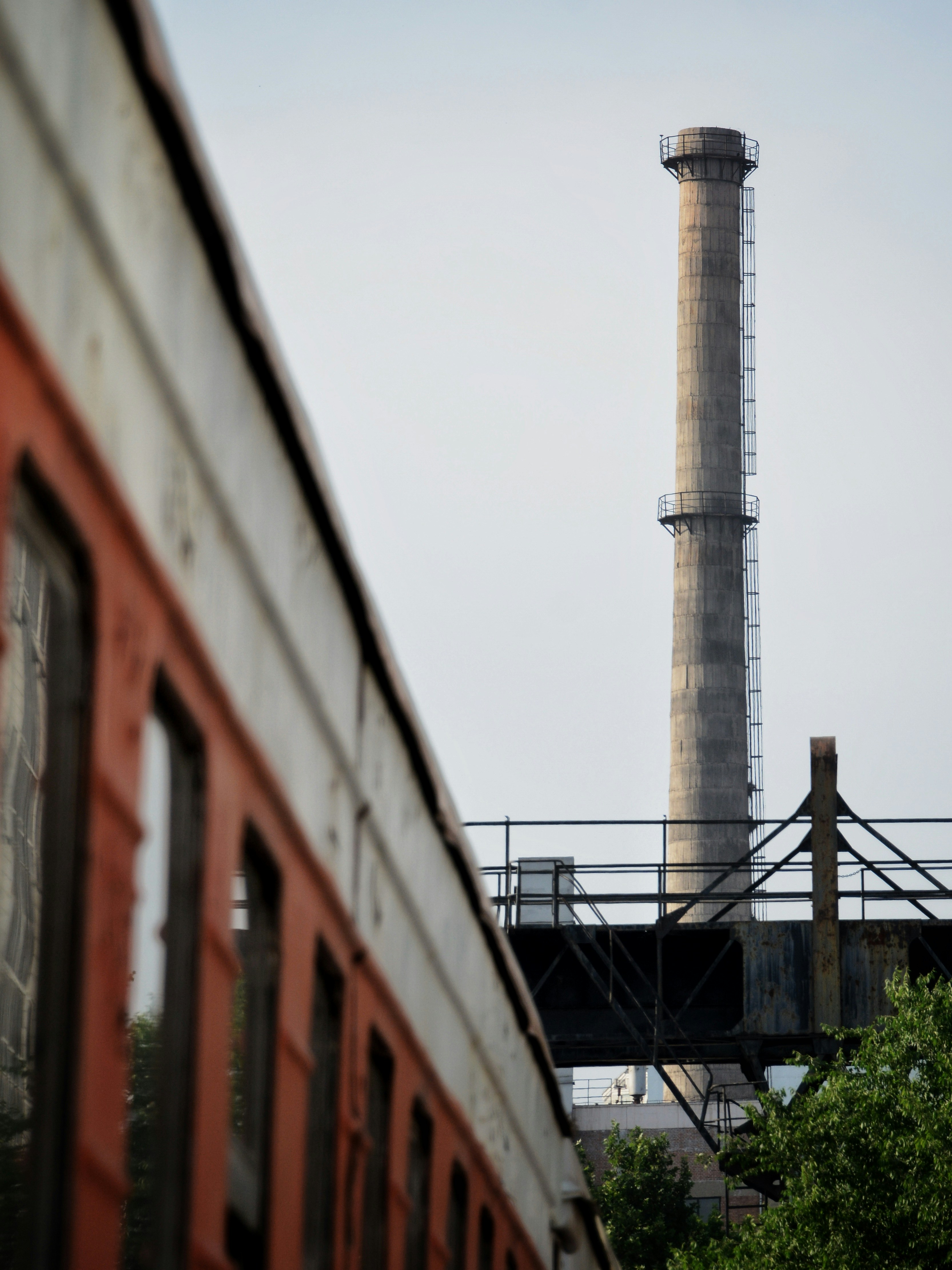 An old train car frames a tall smokestack, hinting at the remnants of industrial activity in a modern landscape.