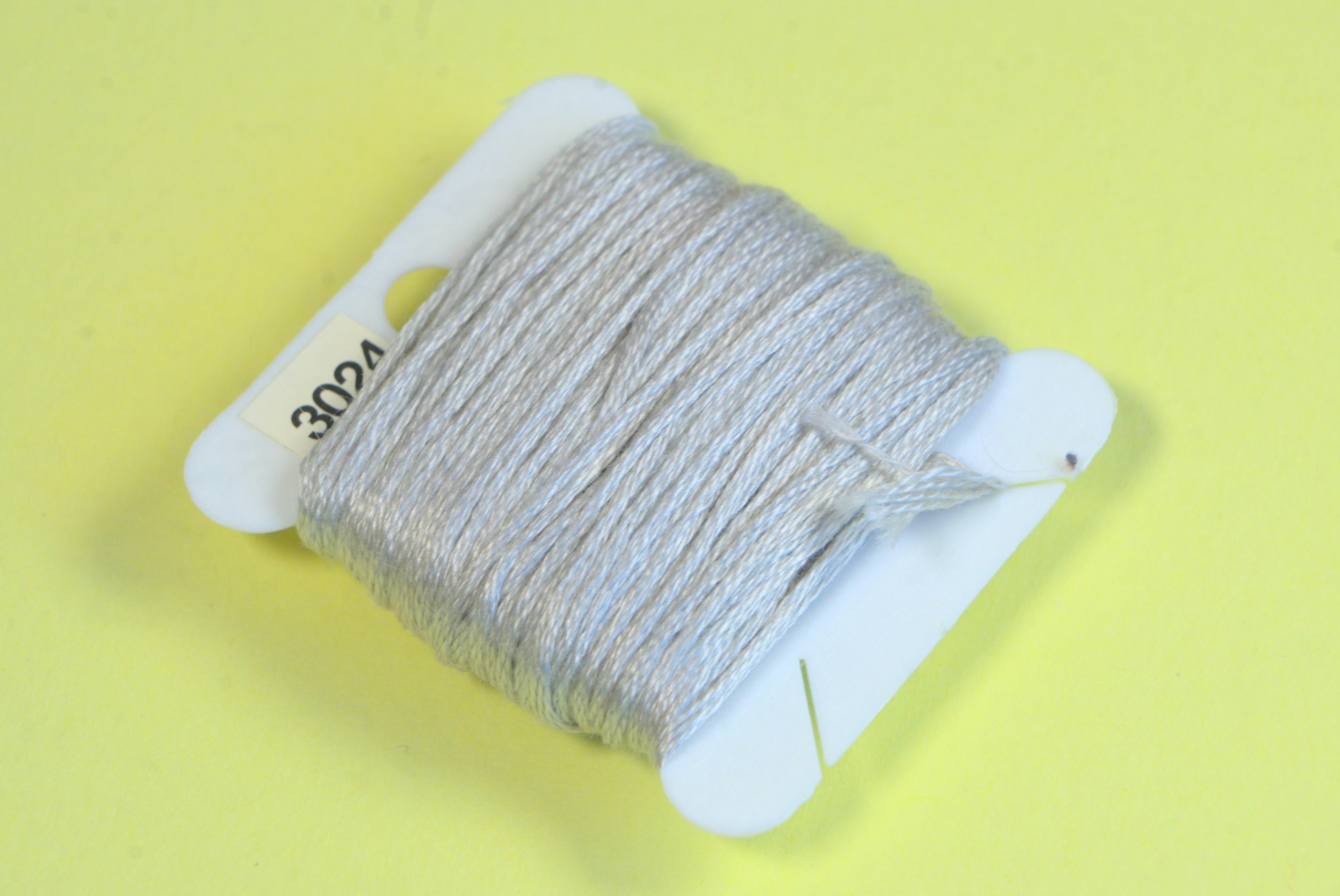 Threaded Skyline: Close-up of Silver Yarn Spool on Yellow