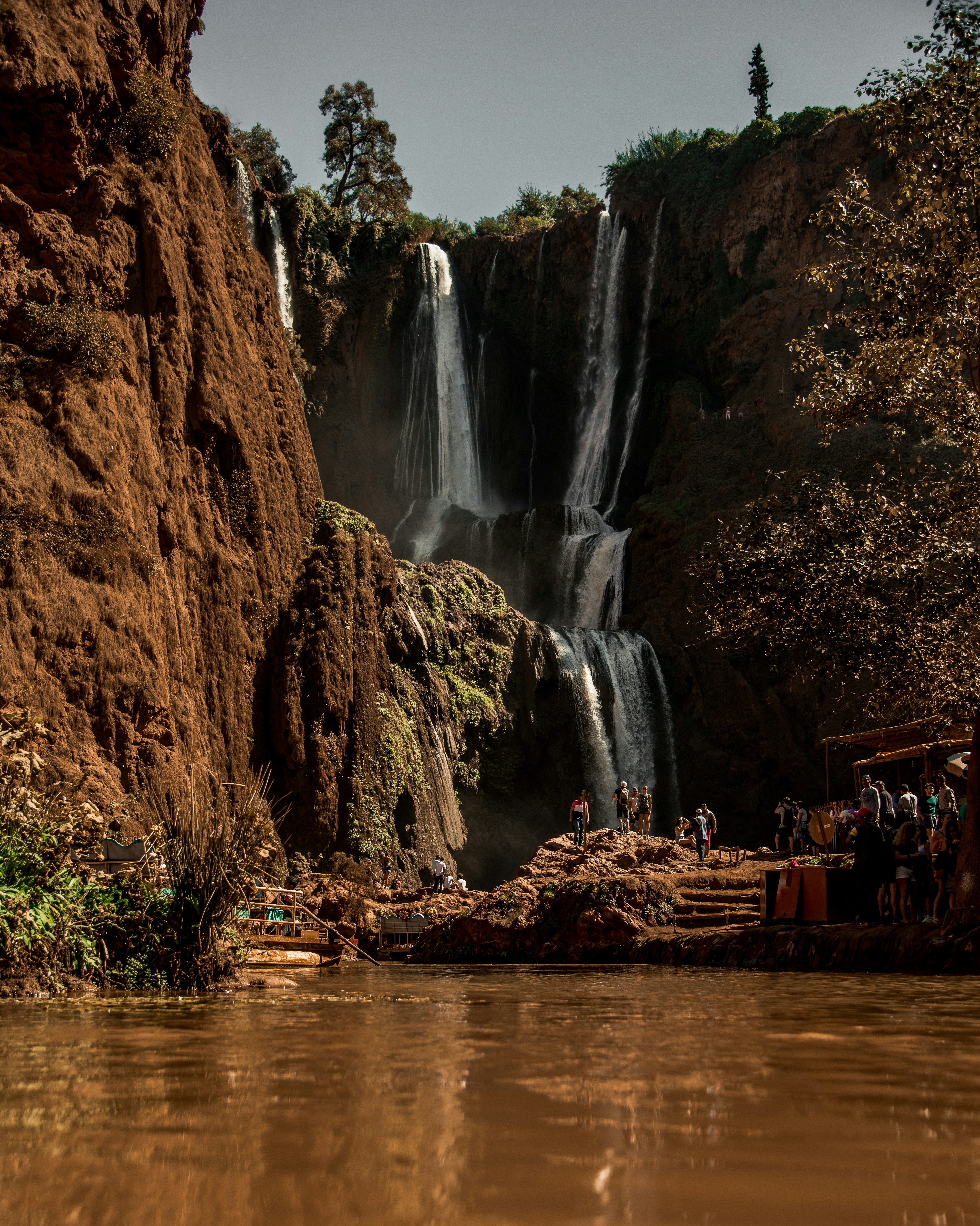 people standing on brown rock formation near waterfalls during daytime