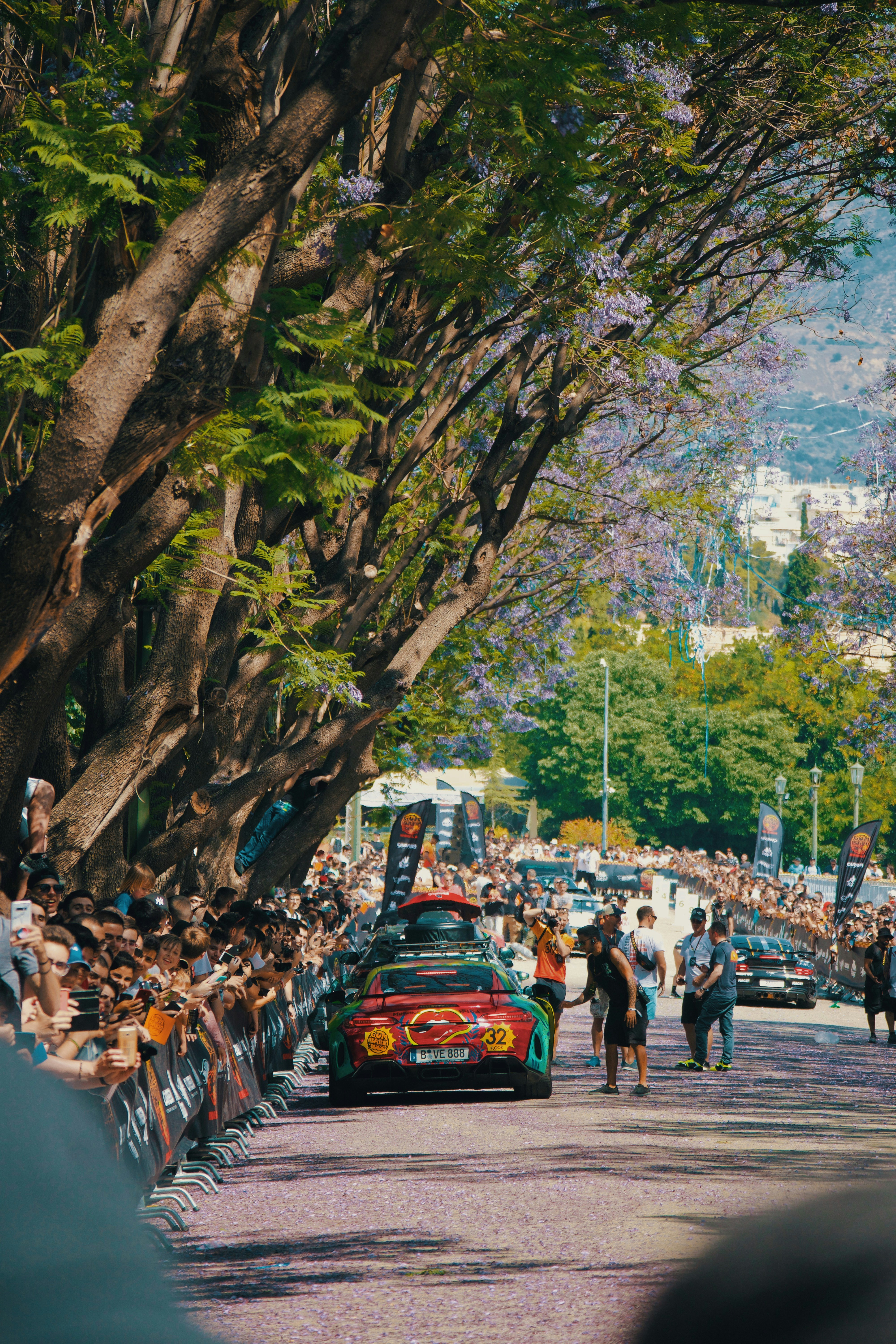 Red Number 32 Car Streaks Through a Sun-Dappled Tree-Lined Boulevard