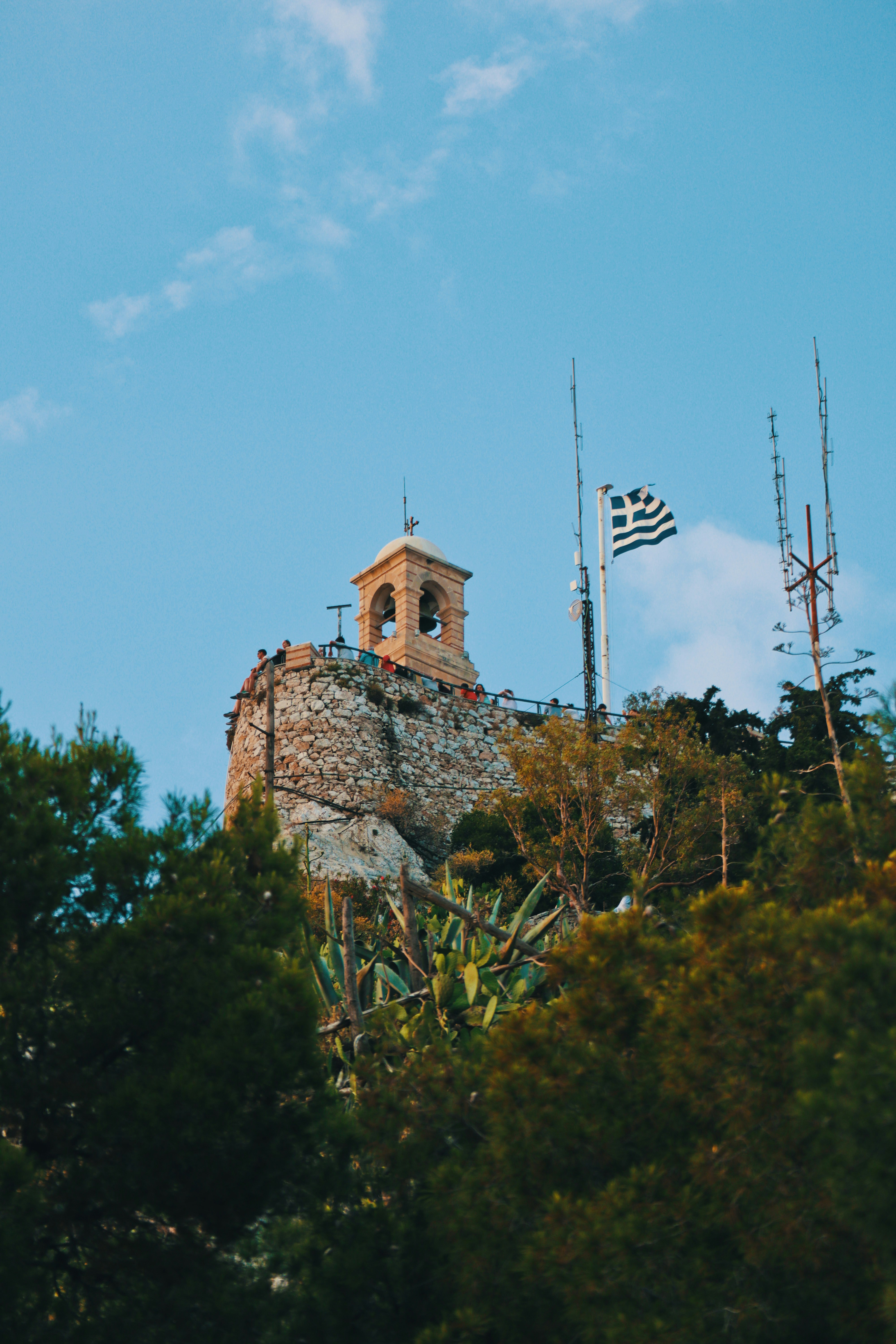 Flag Above the Stone Fortress: Aegean Sky Over a Hillside Citadel