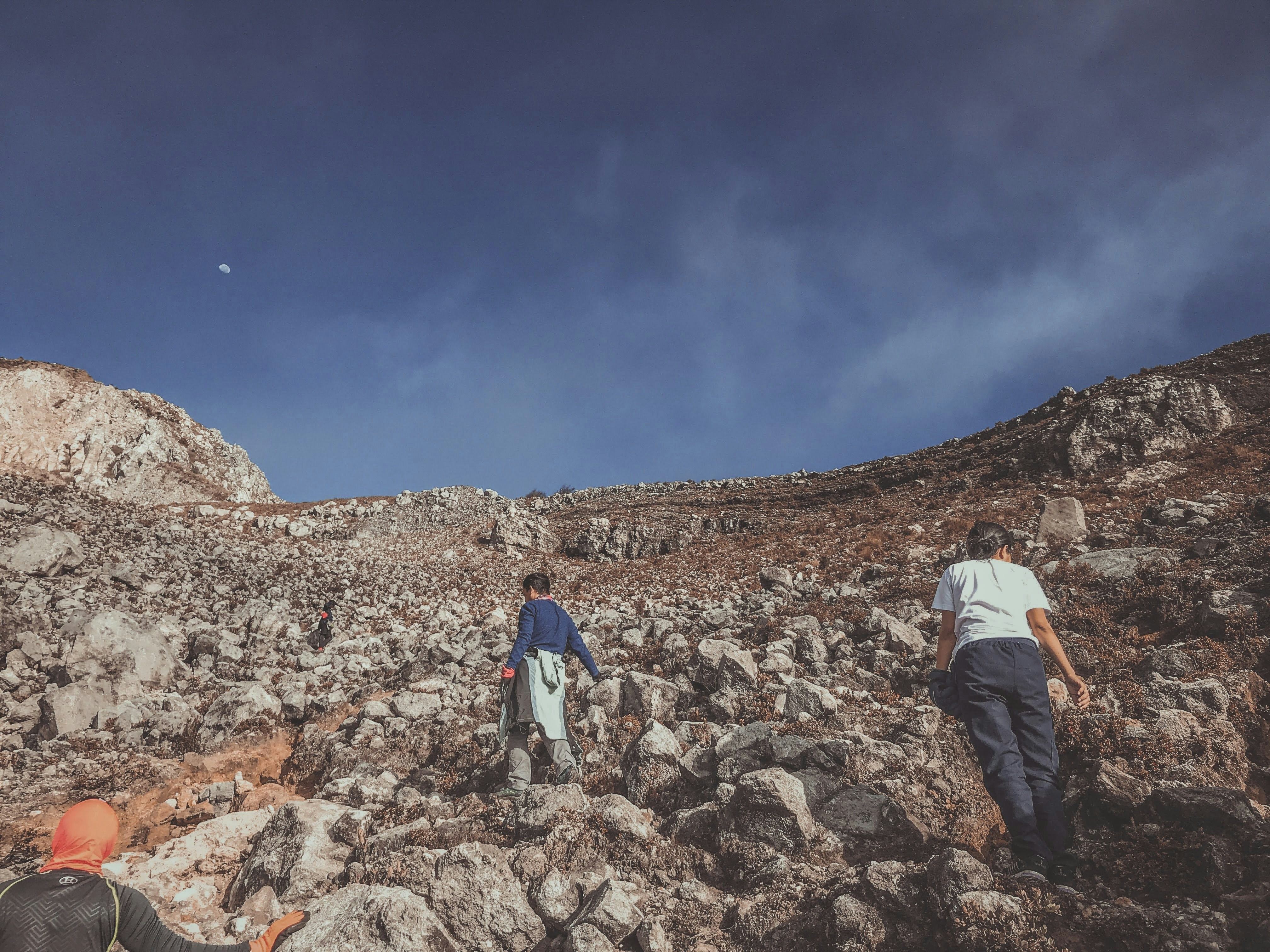 Hikers navigate a rocky landscape under a clear blue sky, showcasing the challenges of outdoor exploration.