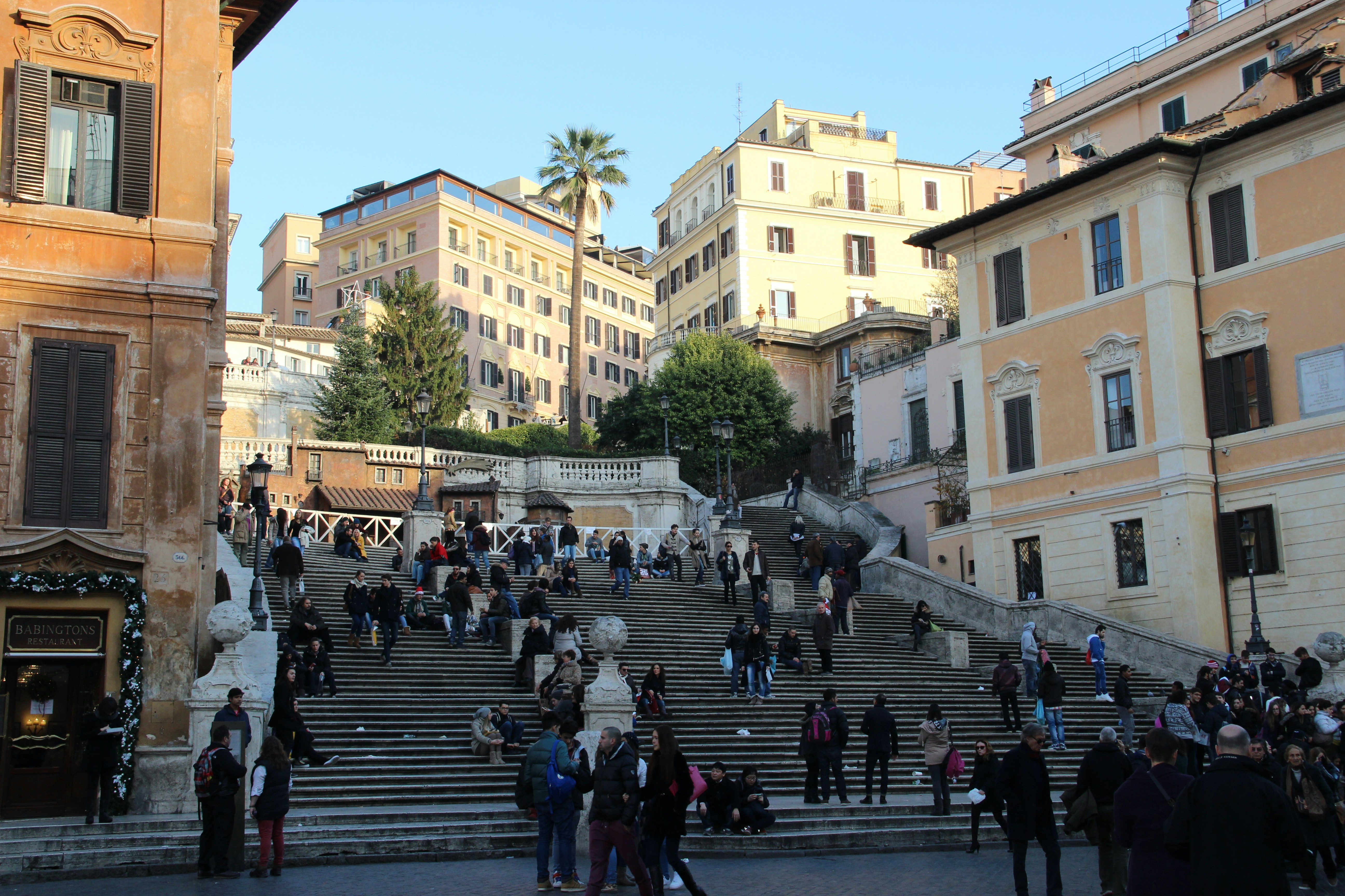 Crowd gathered on the iconic steps of a historic Roman plaza, surrounded by charming architecture and greenery.