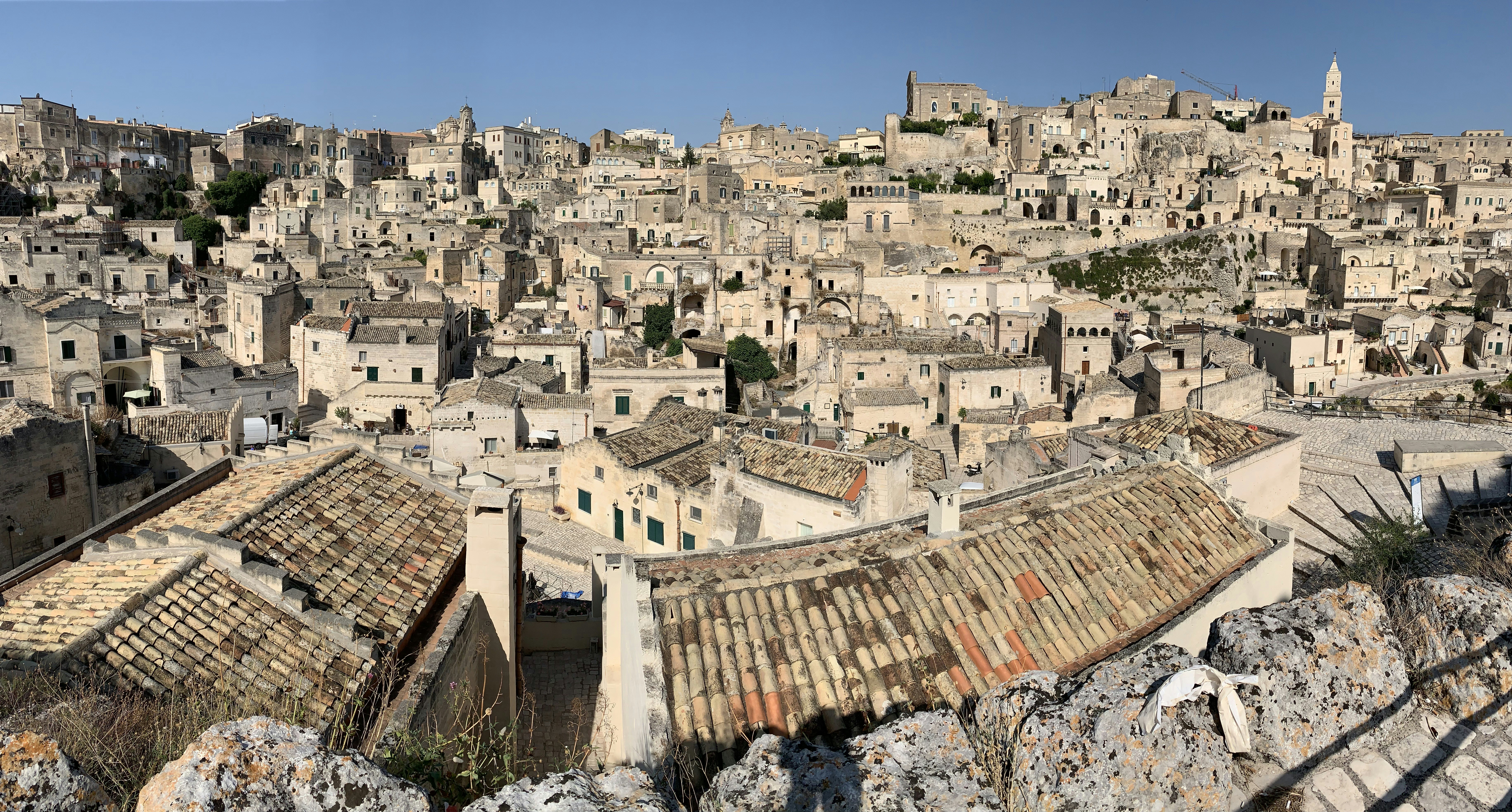Panoramic view of a historic cityscape with densely packed stone buildings under a clear blue sky.