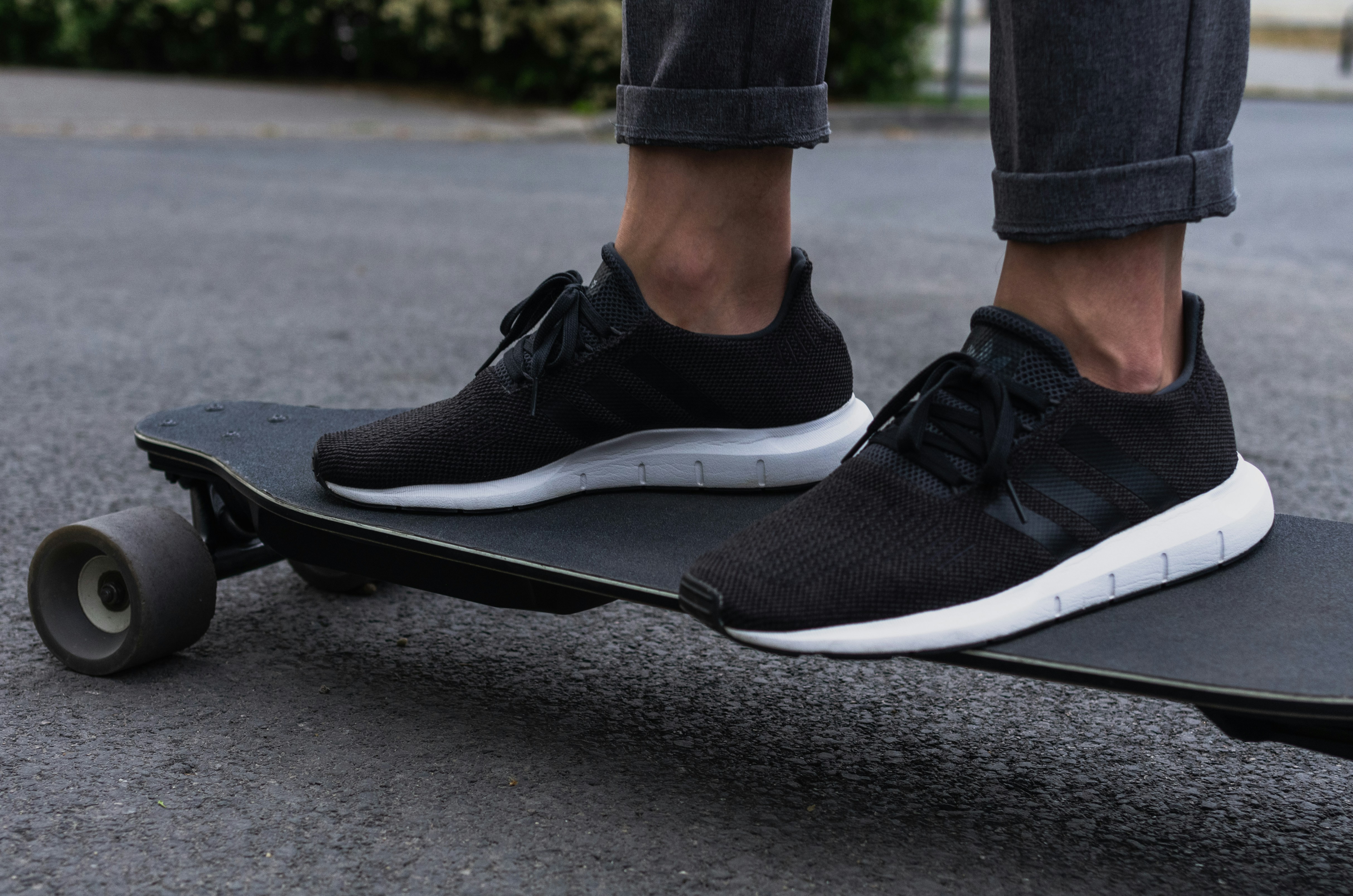 Close-up of a person skateboarding with sleek black sneakers on a smooth asphalt surface.