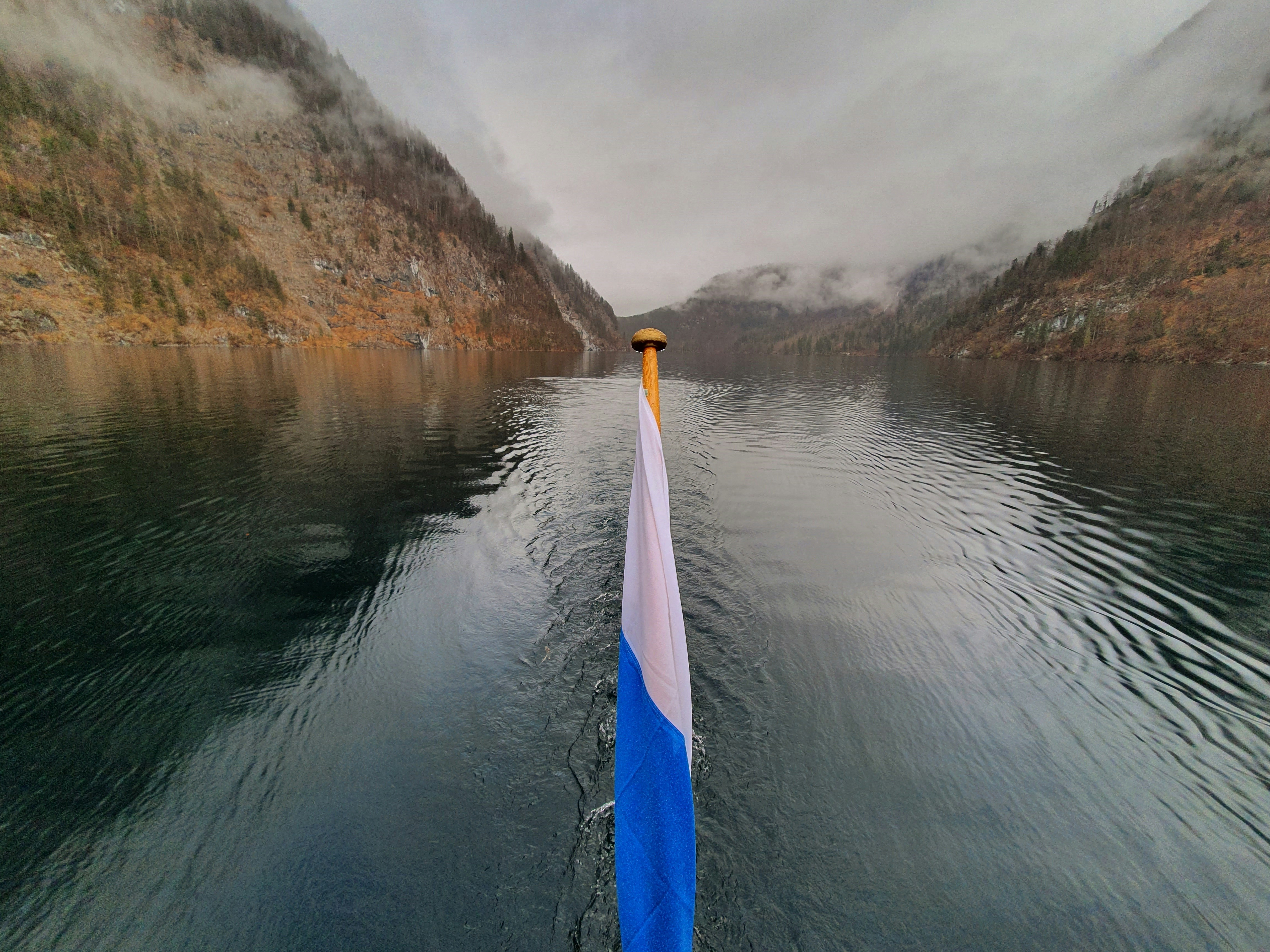blue and yellow flag on body of water near mountain during daytime