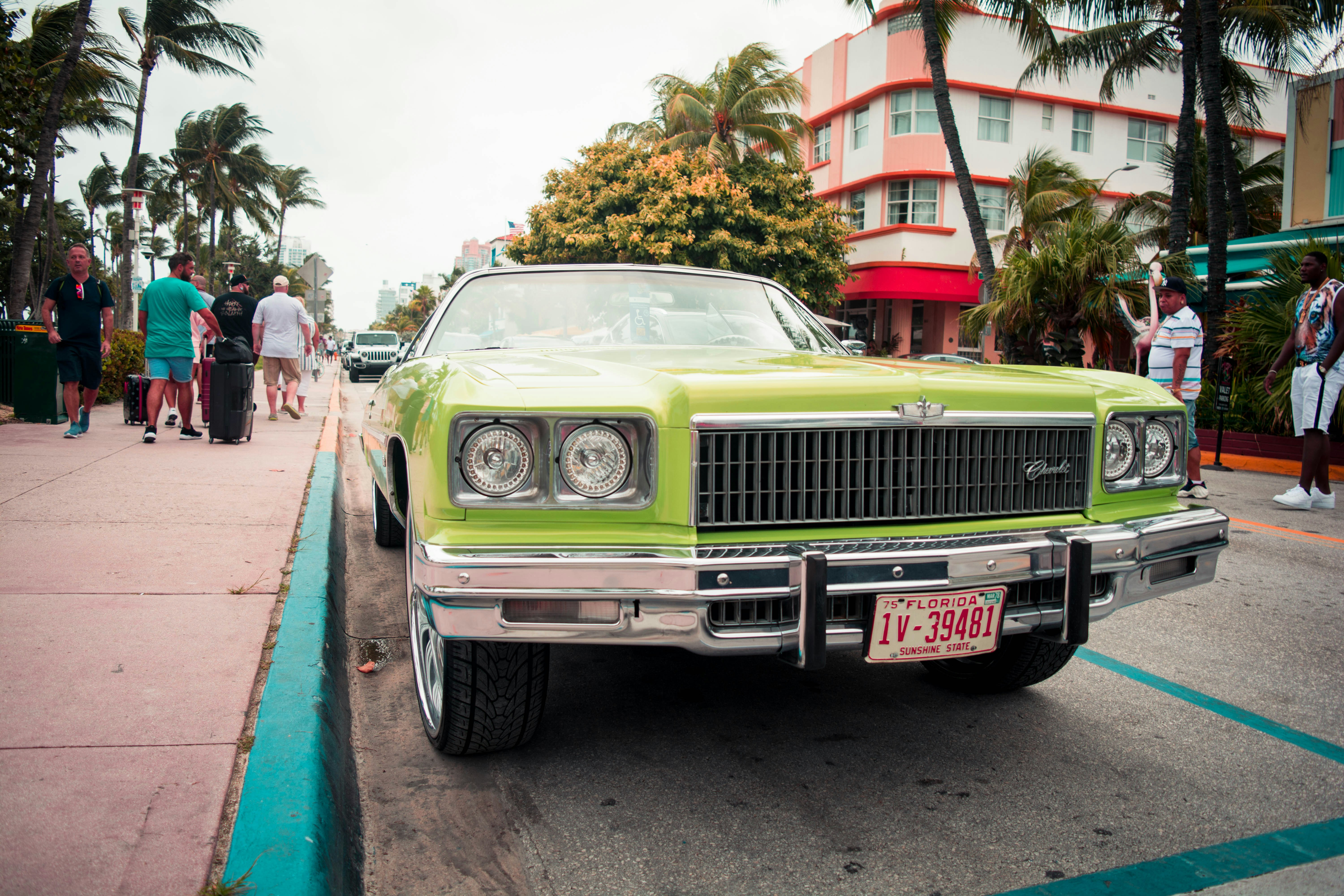  lime-green classic car anchors a palm-lined street scene