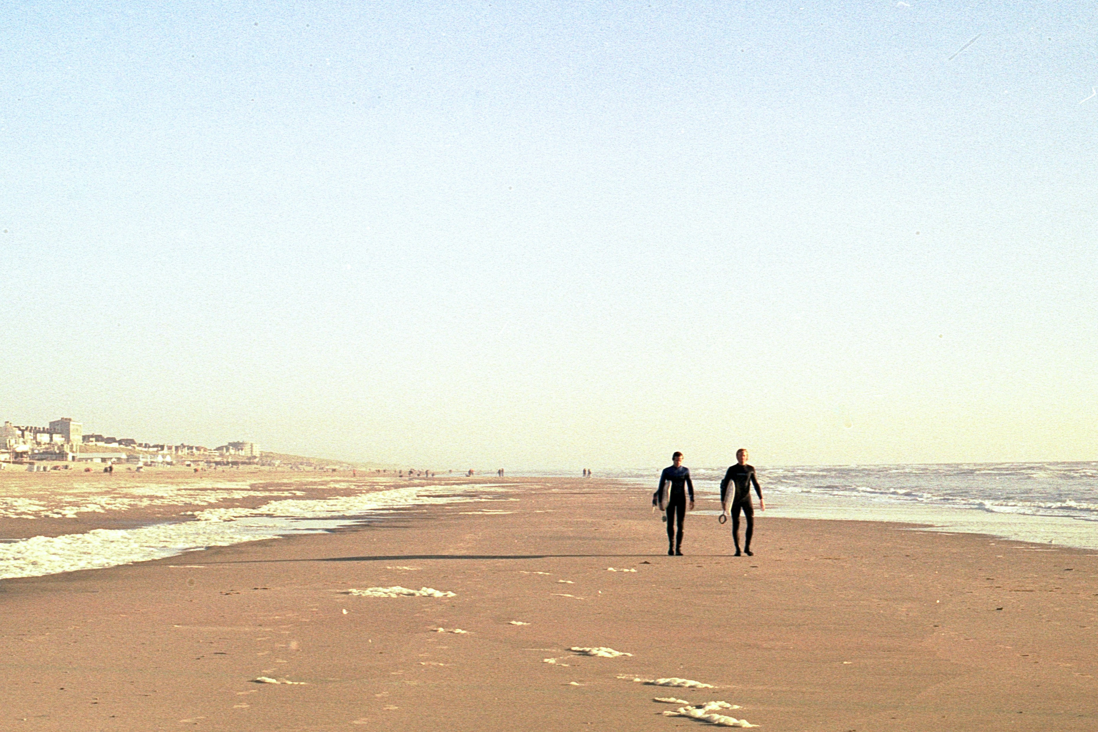 Horizon Walk: Two Figures on a Quiet, Sunlit Beach