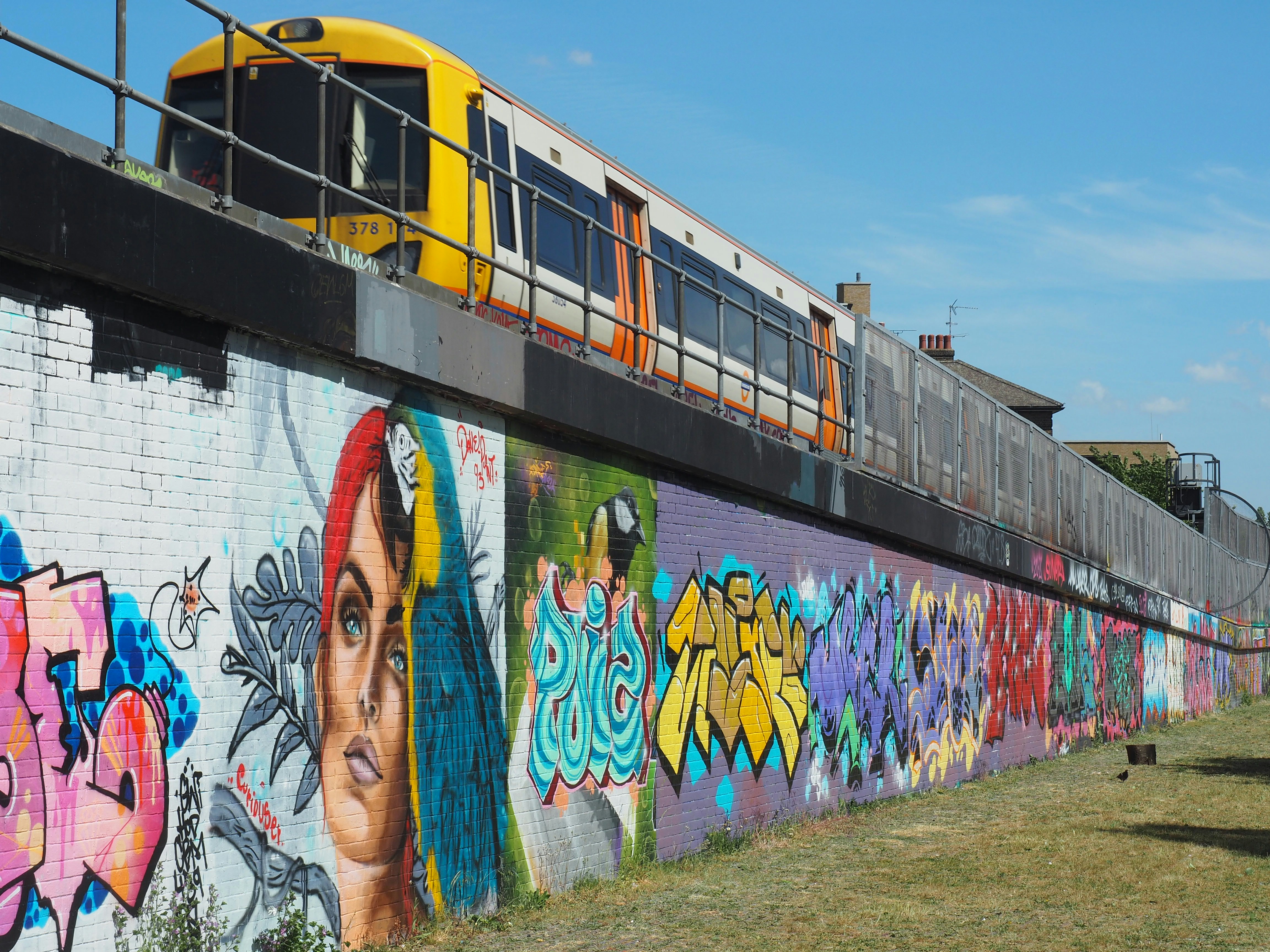 Portrait in Motion Beneath an Elevated Train: A Neon Graffiti Corridor