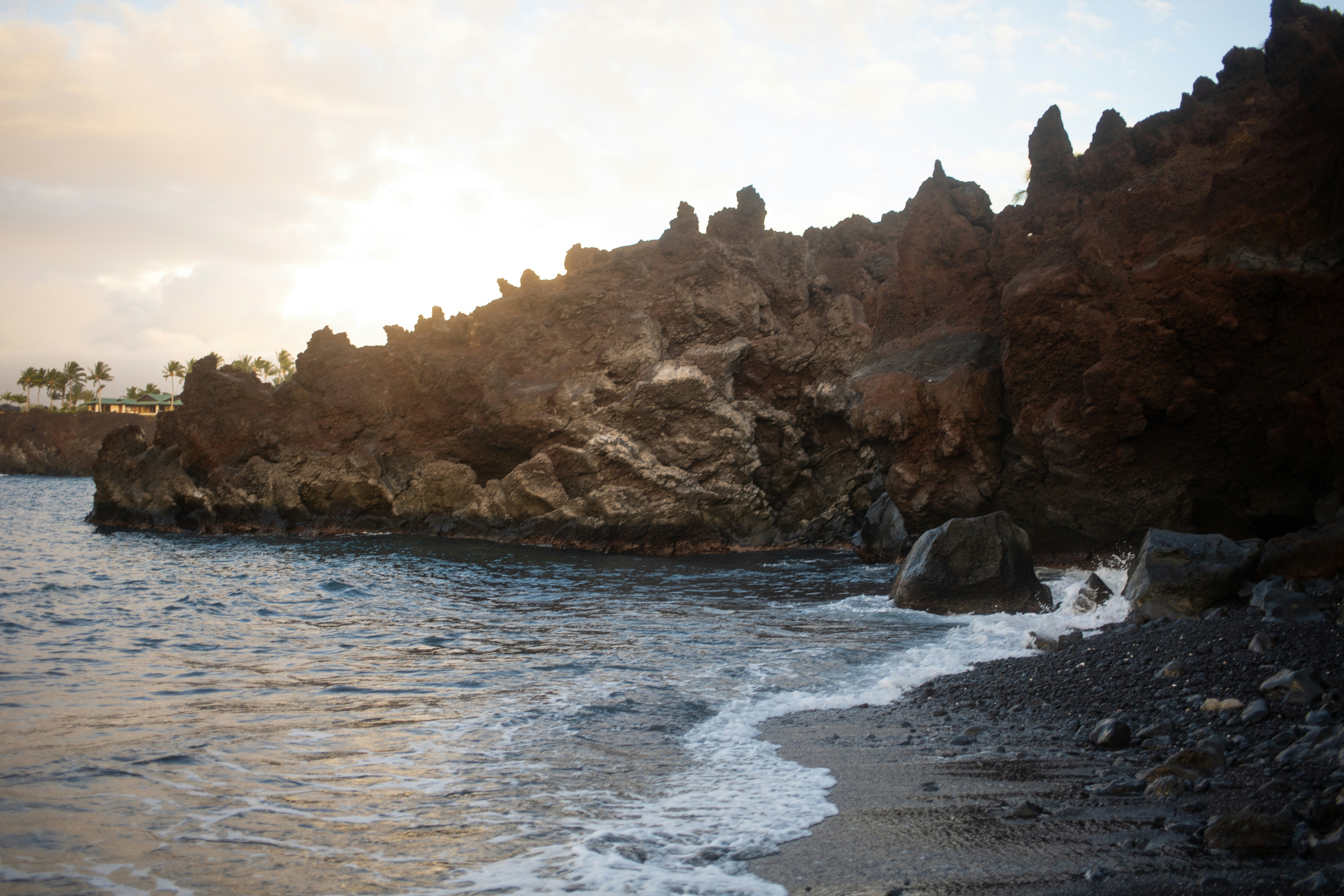 Sunlit Basalt Edge: Lava-Cliff Coast Meets a Pebble Shore