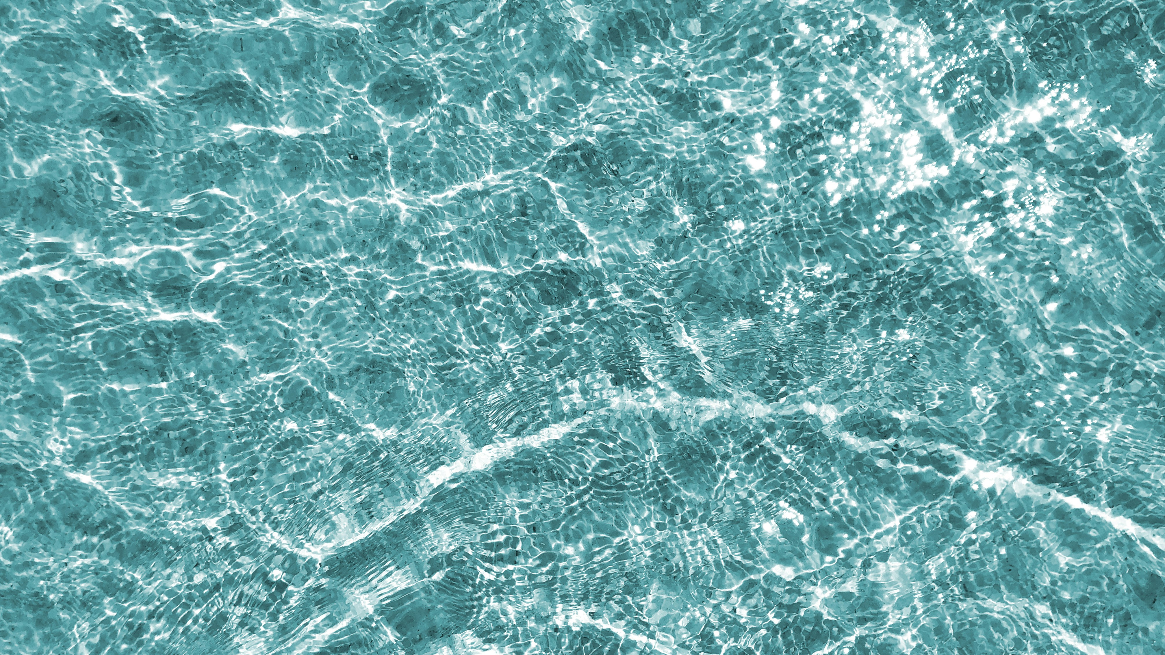 Turquoise water surface with dynamic white patterns.