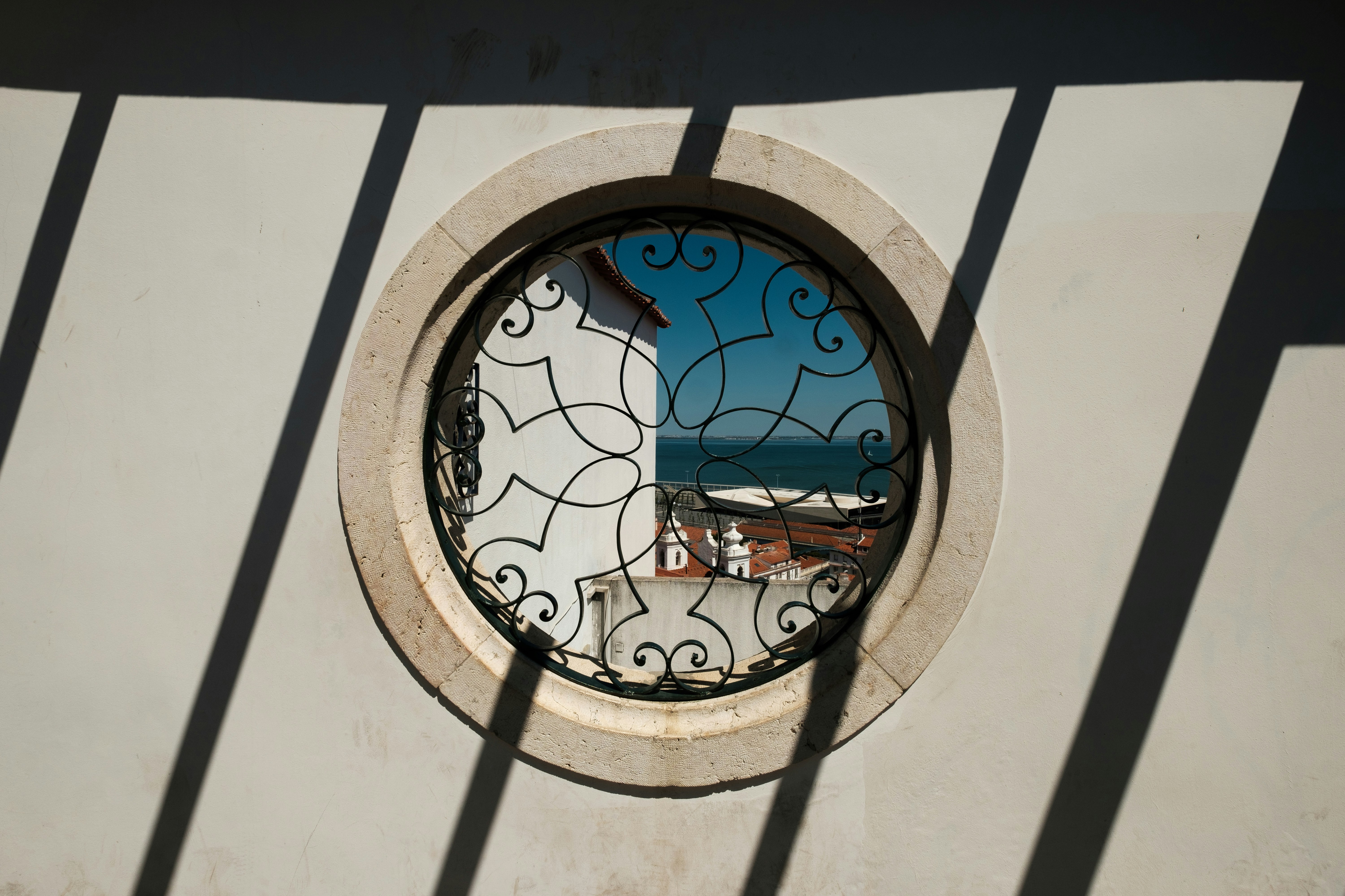 Oculus and Shadows: Seaside Town Through a Wrought-Iron Circle