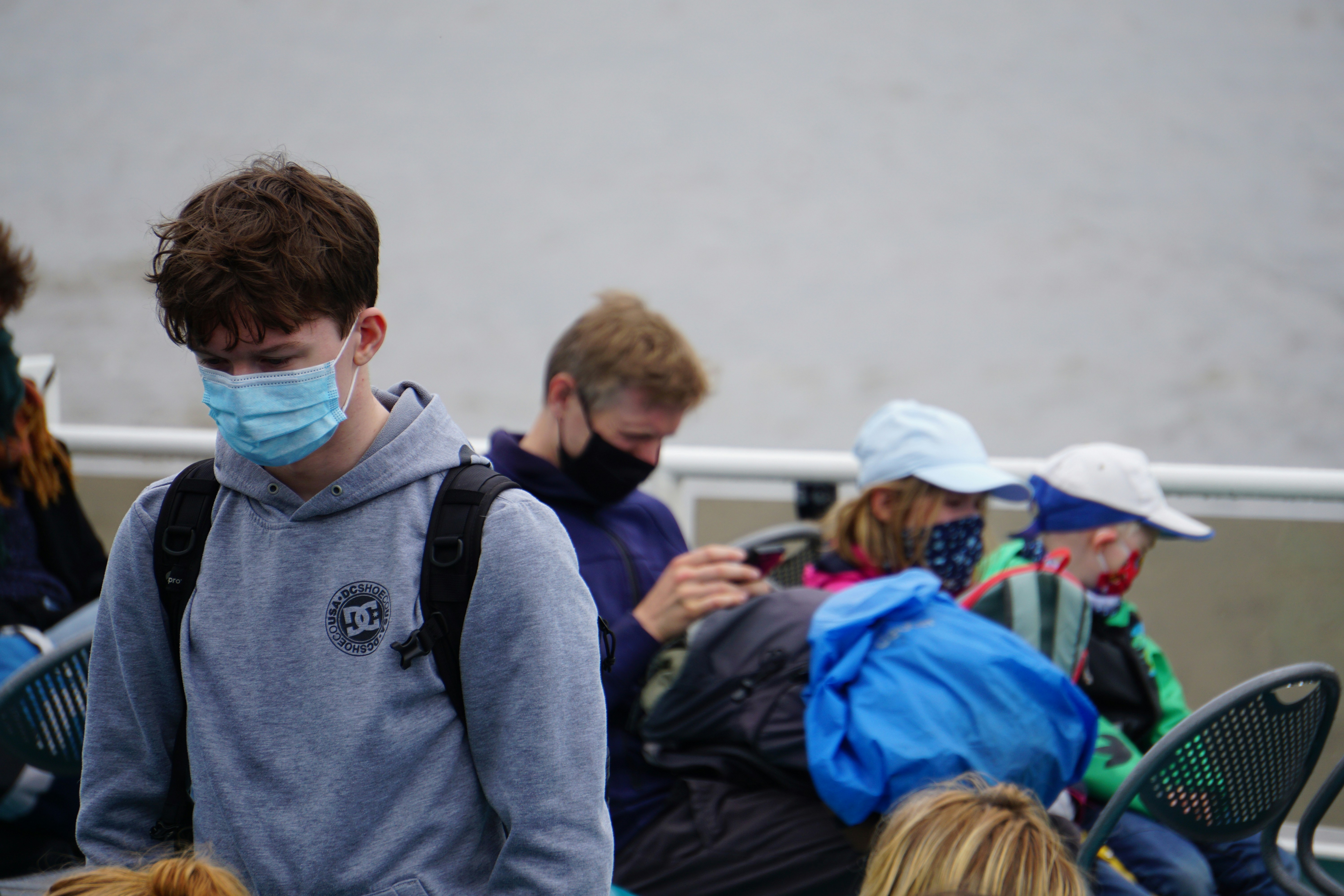 Hooded Foreground, Masked Group on a Waterfront Ferry Deck