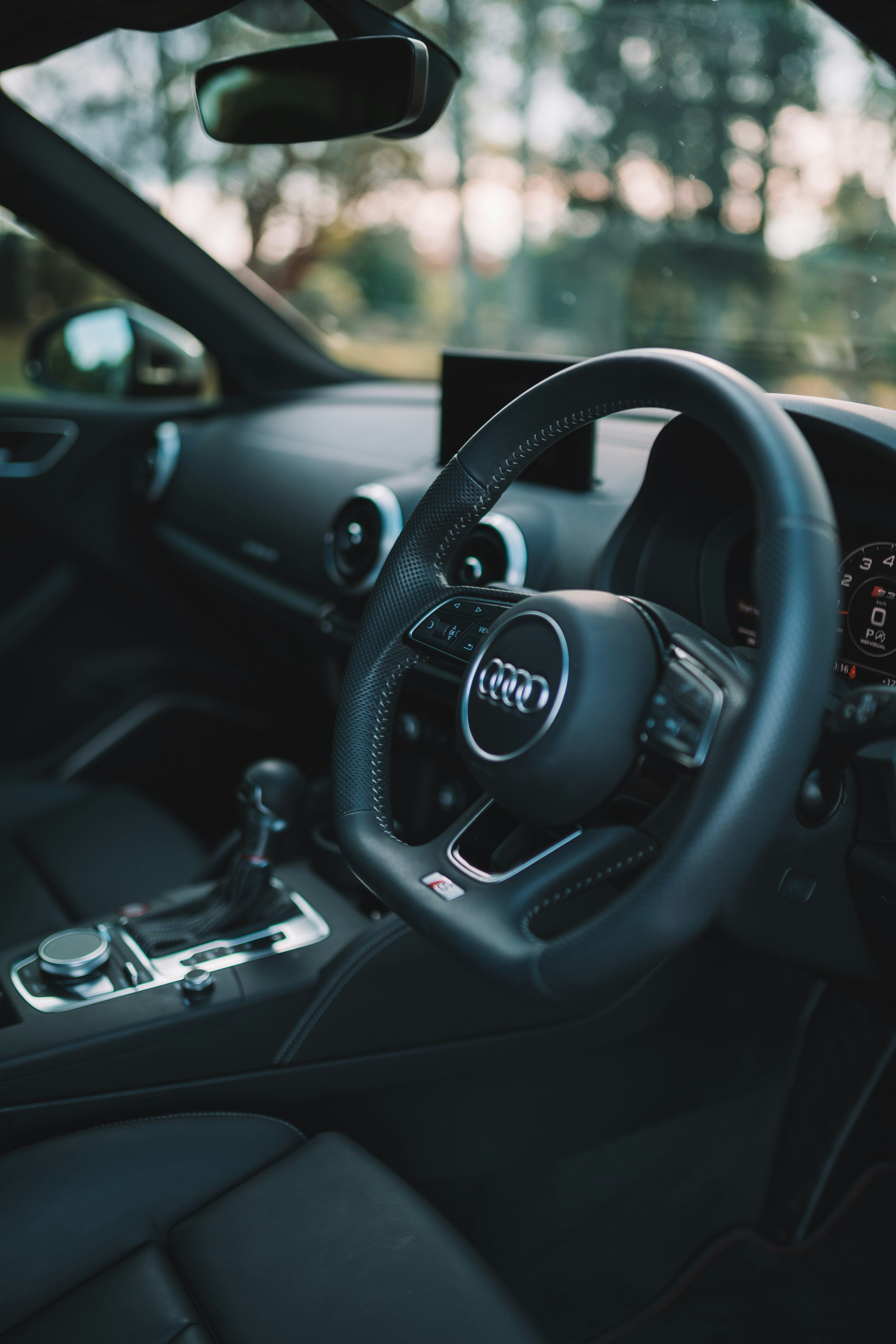 Interior view of an Audi car showcasing the sleek steering wheel, gear shift, and modern dashboard design.