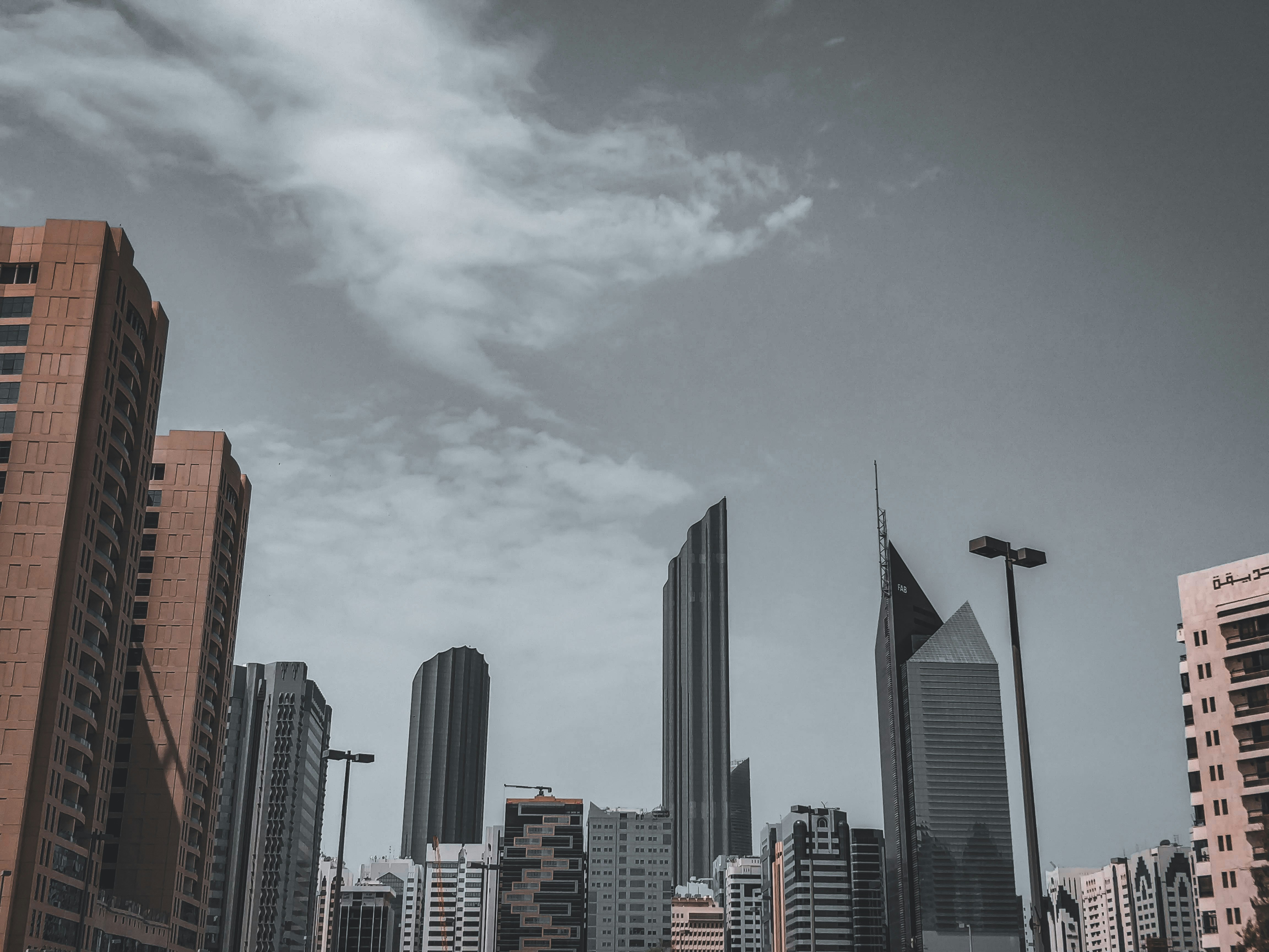 High-rise buildings under a dramatic, cloudy sky create a modern cityscape.