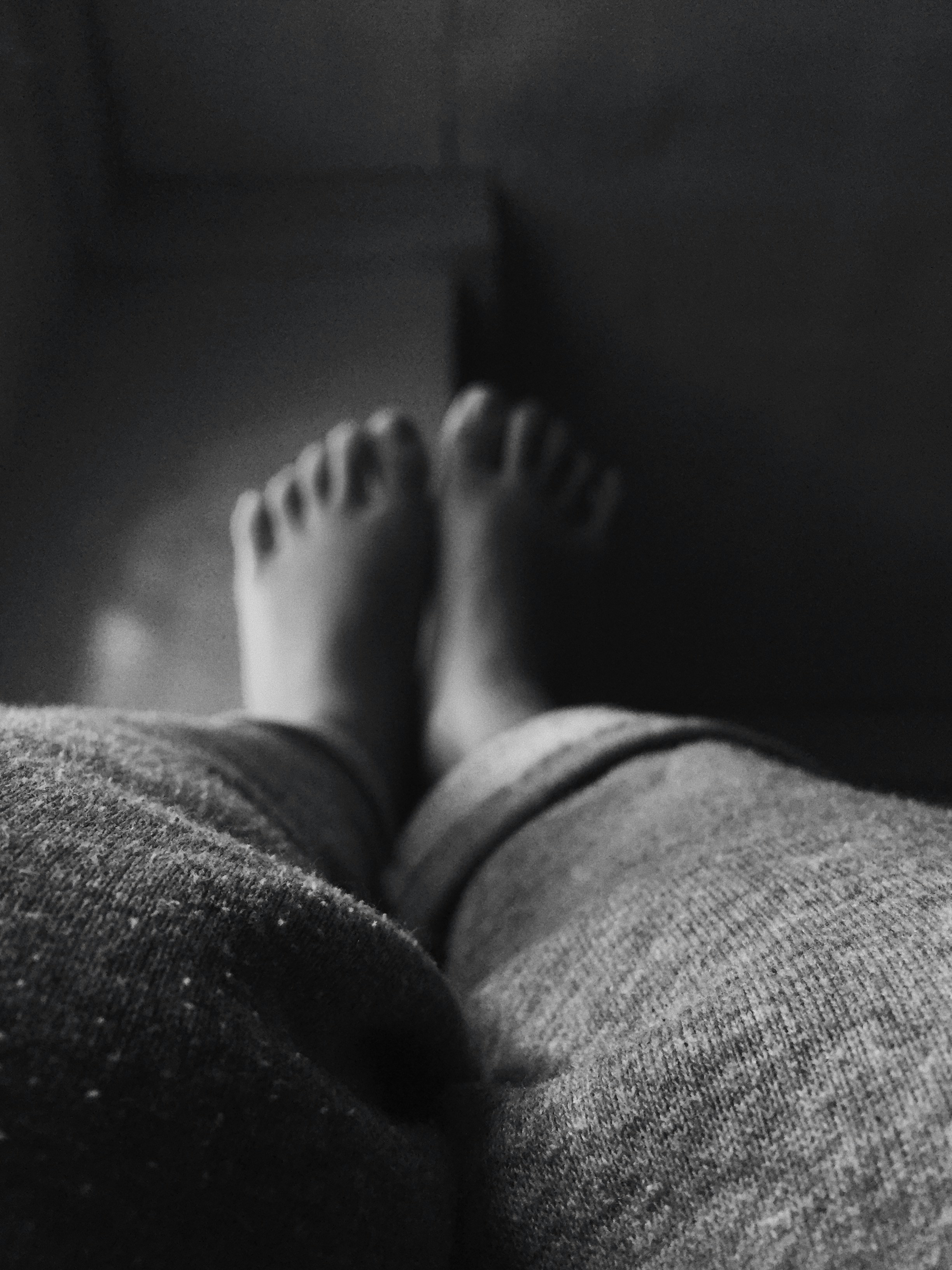 Bare feet resting on a smooth surface, framed by casual gray pants, creating a serene and introspective atmosphere.