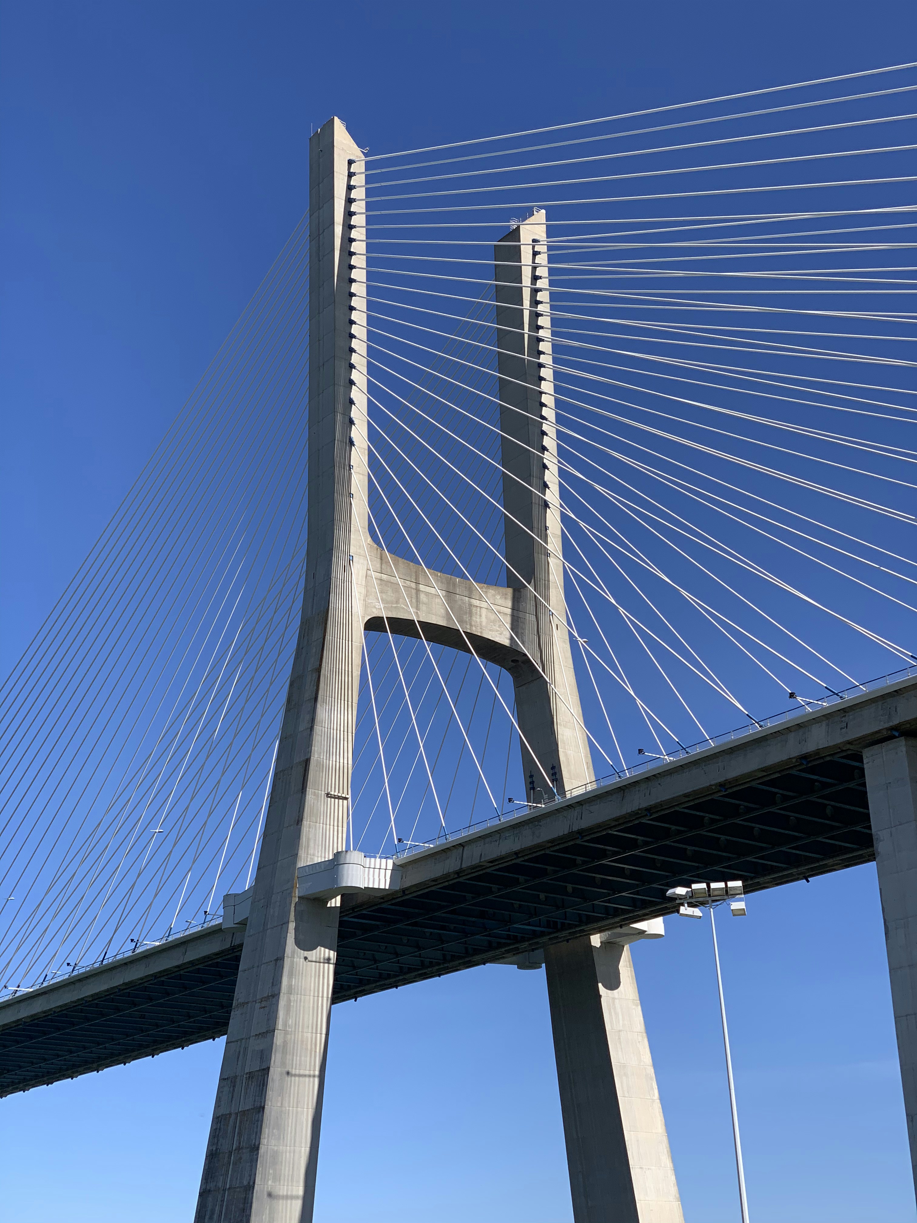 A modern cable-stayed bridge showcases its towering pylons and intricate cable work against a clear blue sky.