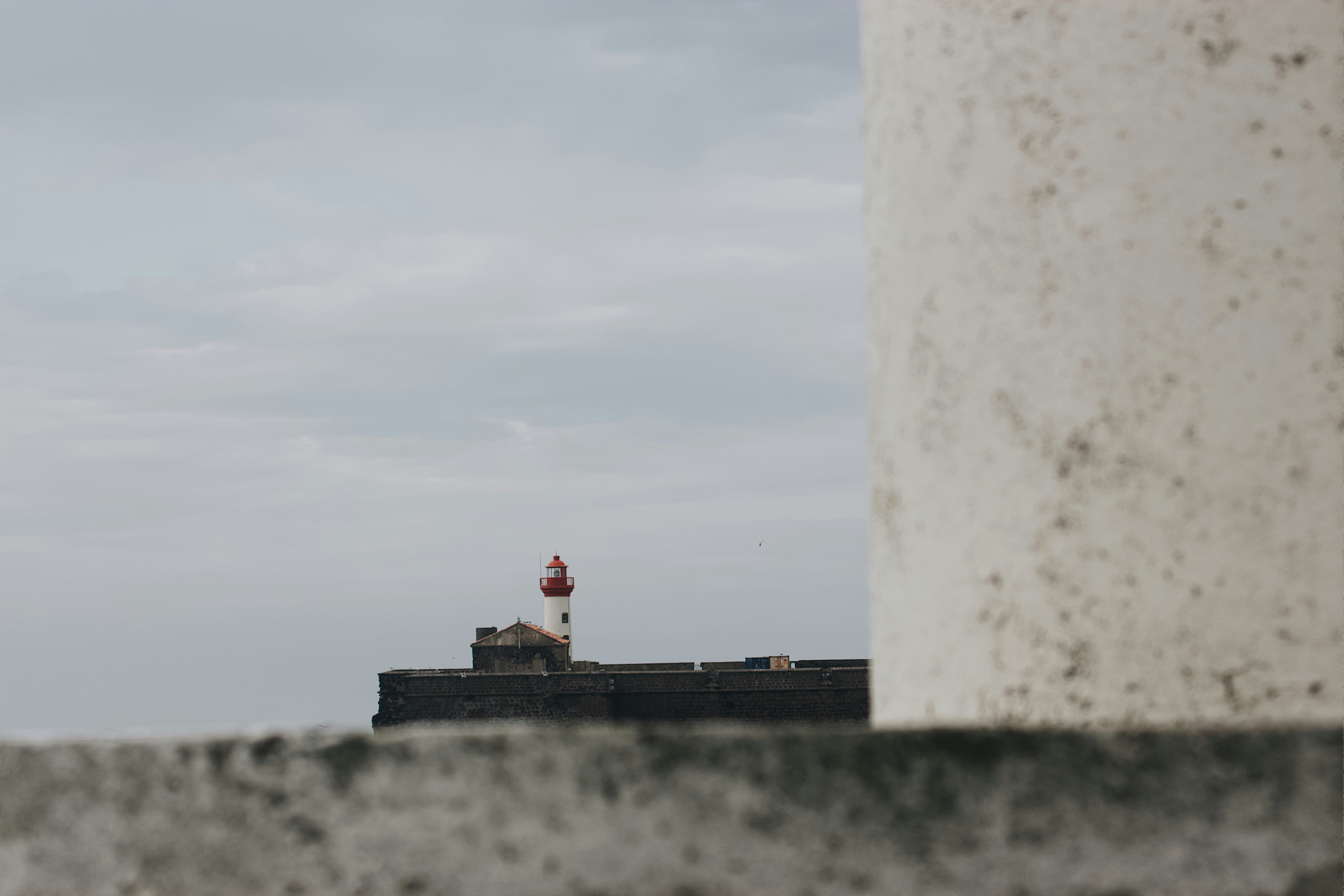 Lighthouse Sentinel Across a Weathered Breakwater Under Steel-Gray Skies