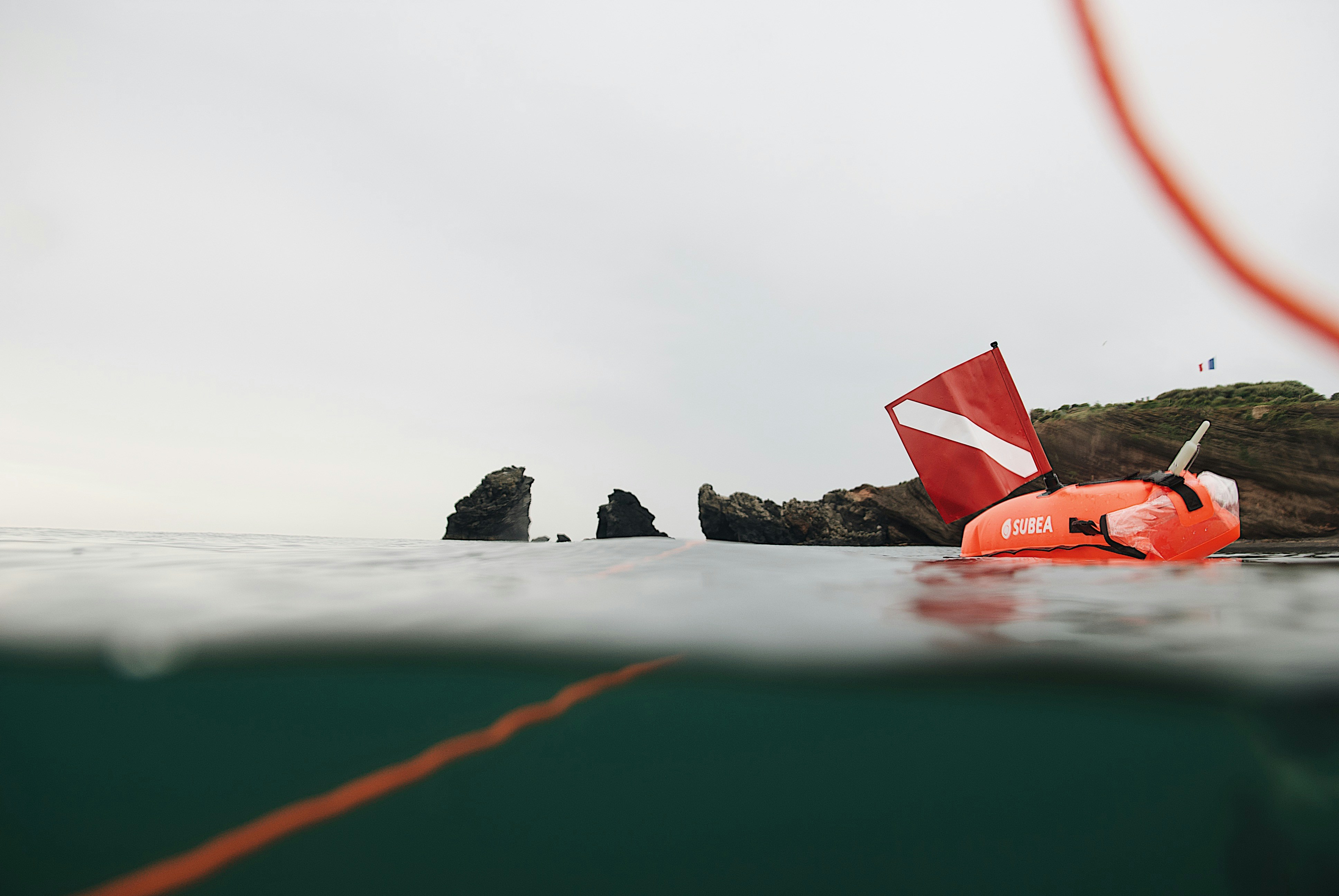 Low-Depth Orange Lifeboat Drifts Near Rock Outcrops at Sea