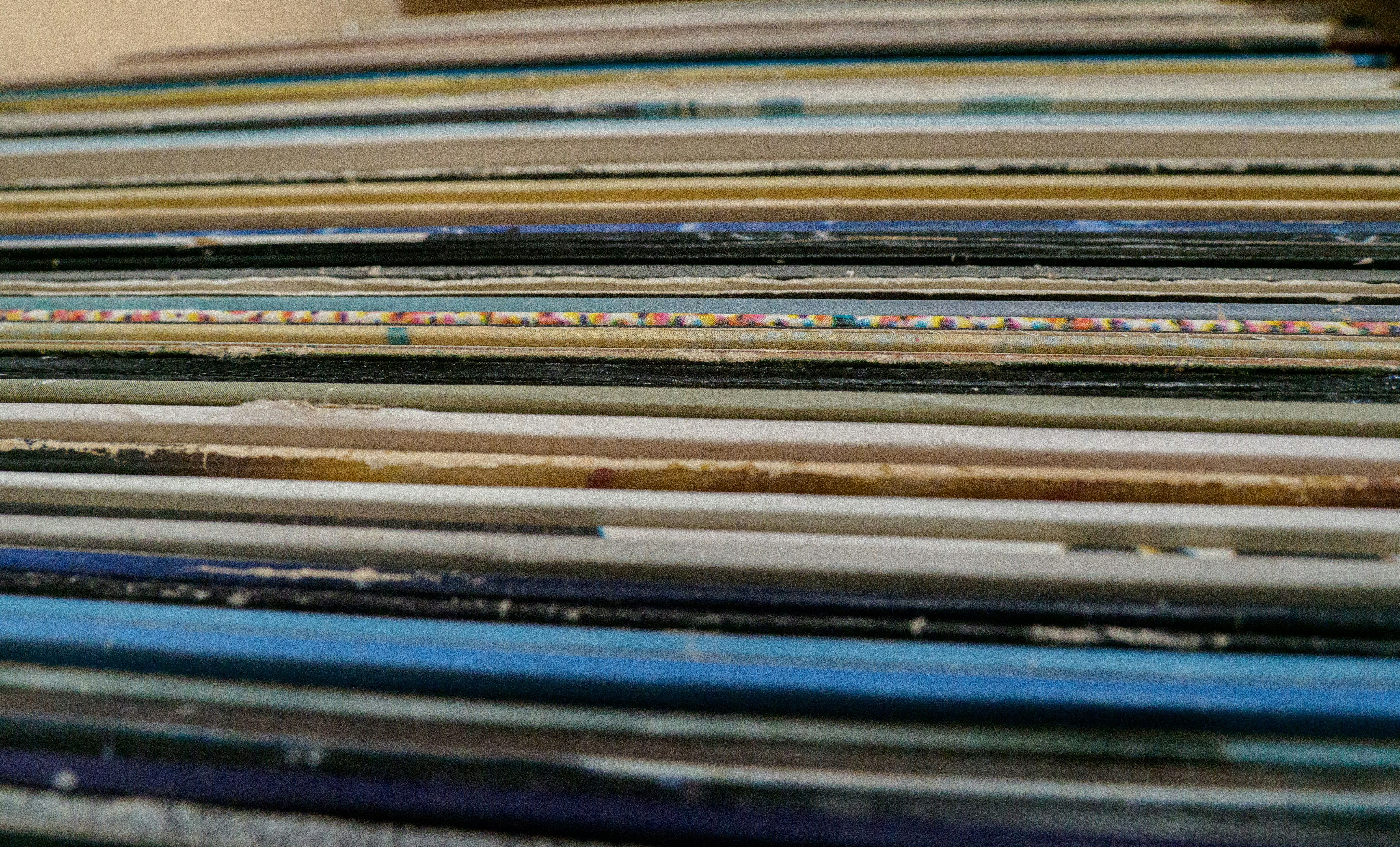 A close-up view of stacked vinyl records showcasing their colorful spines and textures. The arrangement highlights the nostalgia and artistry of analog music storage.