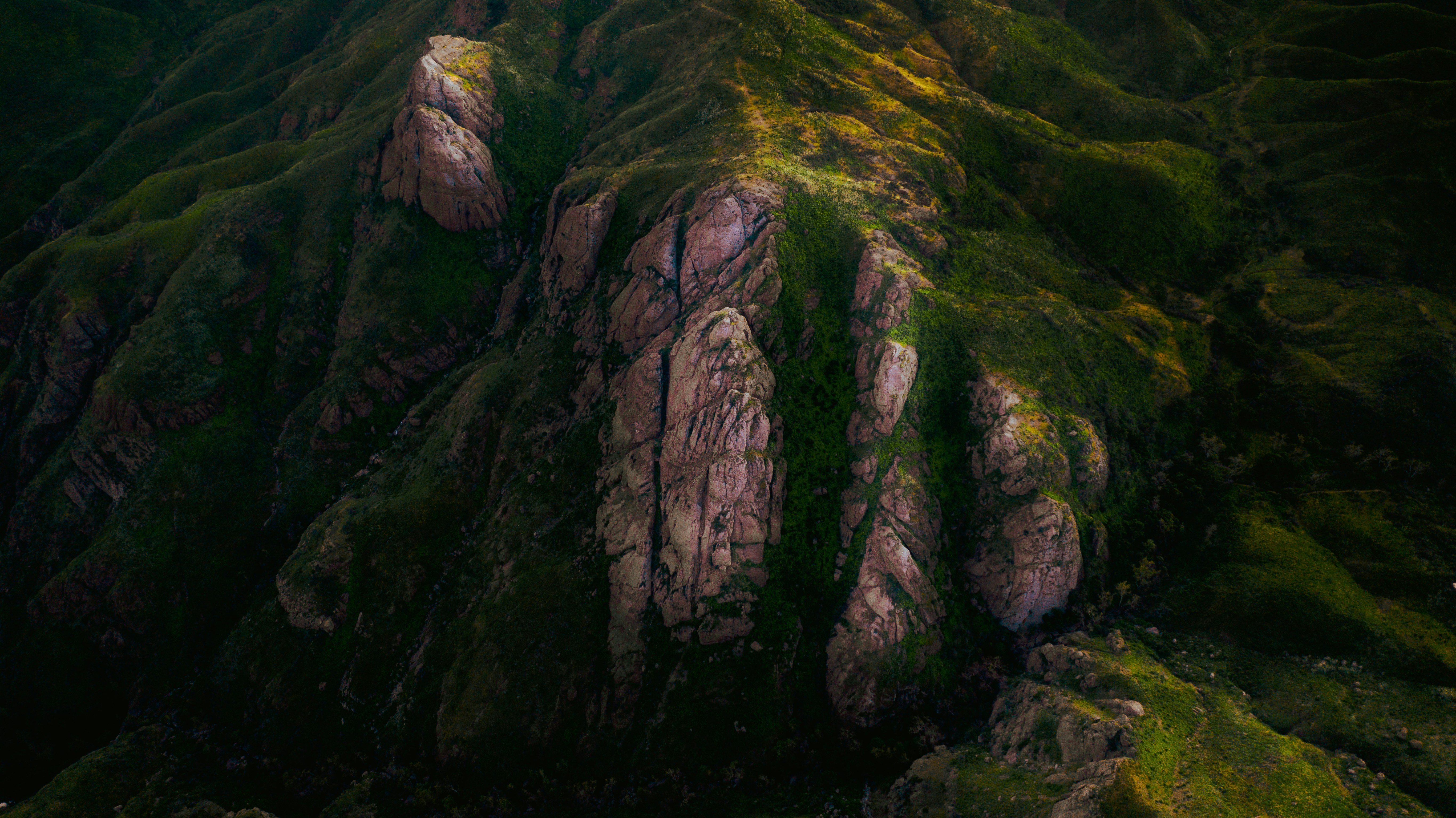 Lush green hills with striking rock formations basking in soft sunlight.