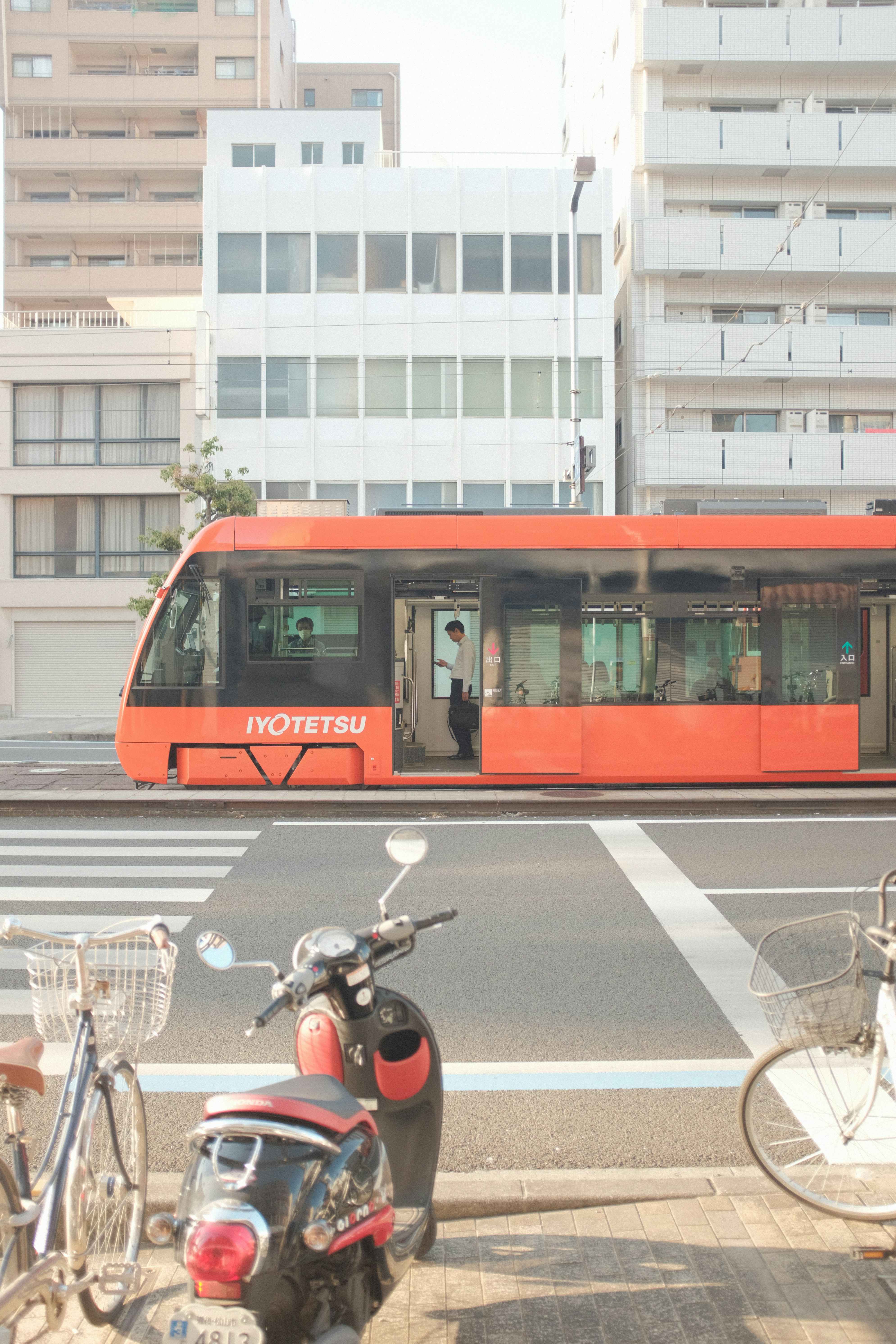 A red bus driving down a street next to tall buildings photo – Free ...