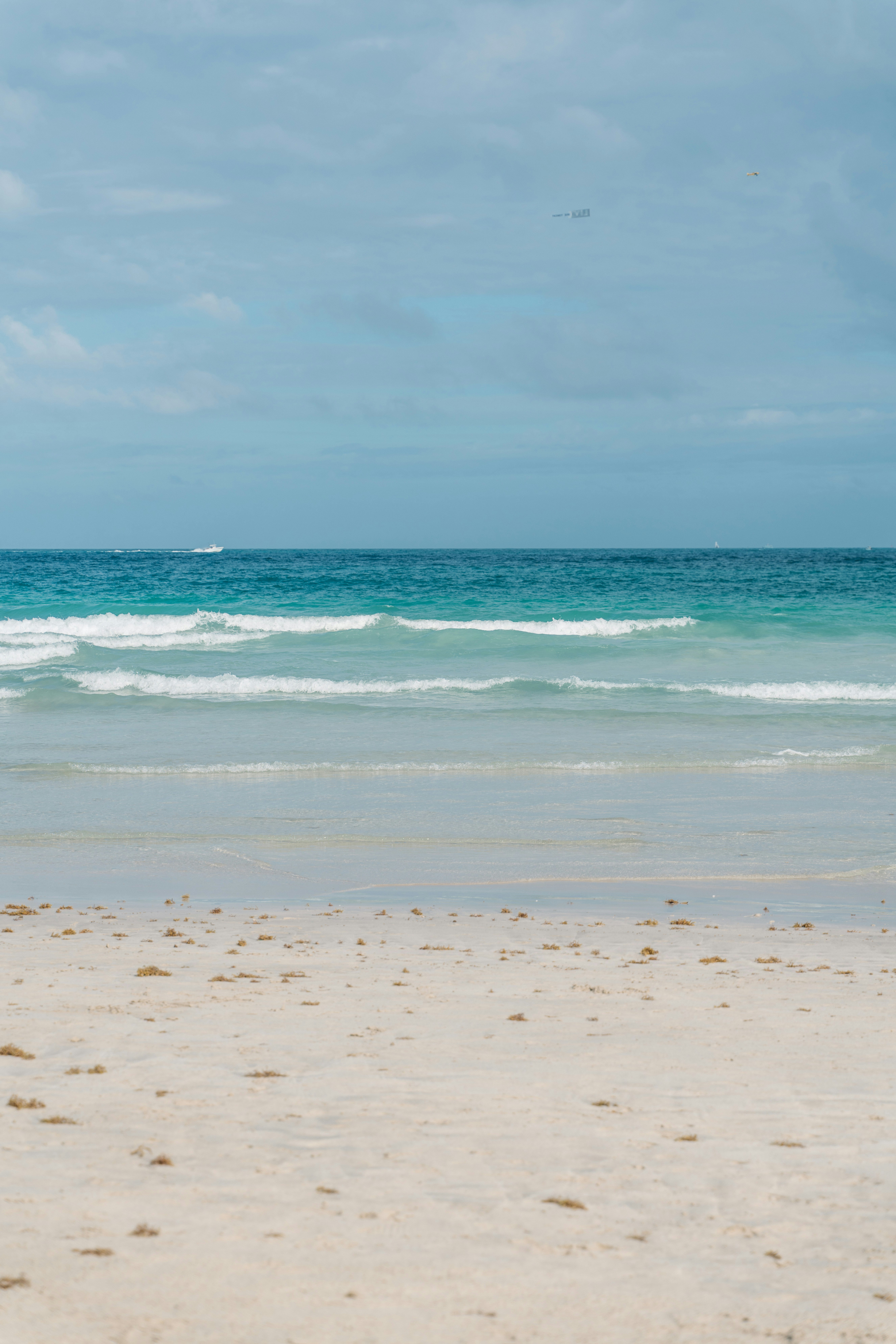 Gentle waves lapping against a sandy beach under a cloudy sky, evoking a sense of calm and tranquility.