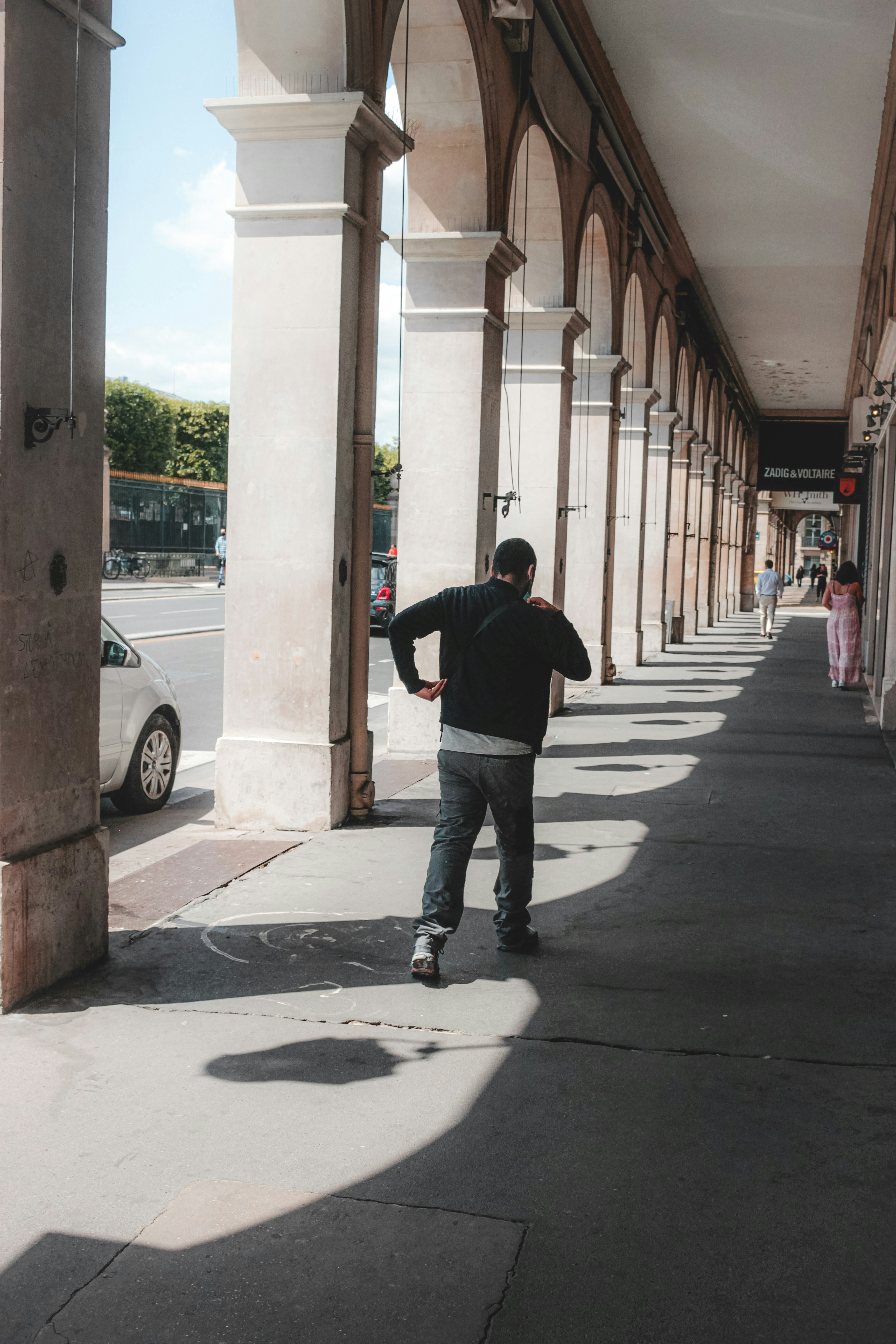 Arcade Walk: A Lone Figure under Sunlit Colonnades