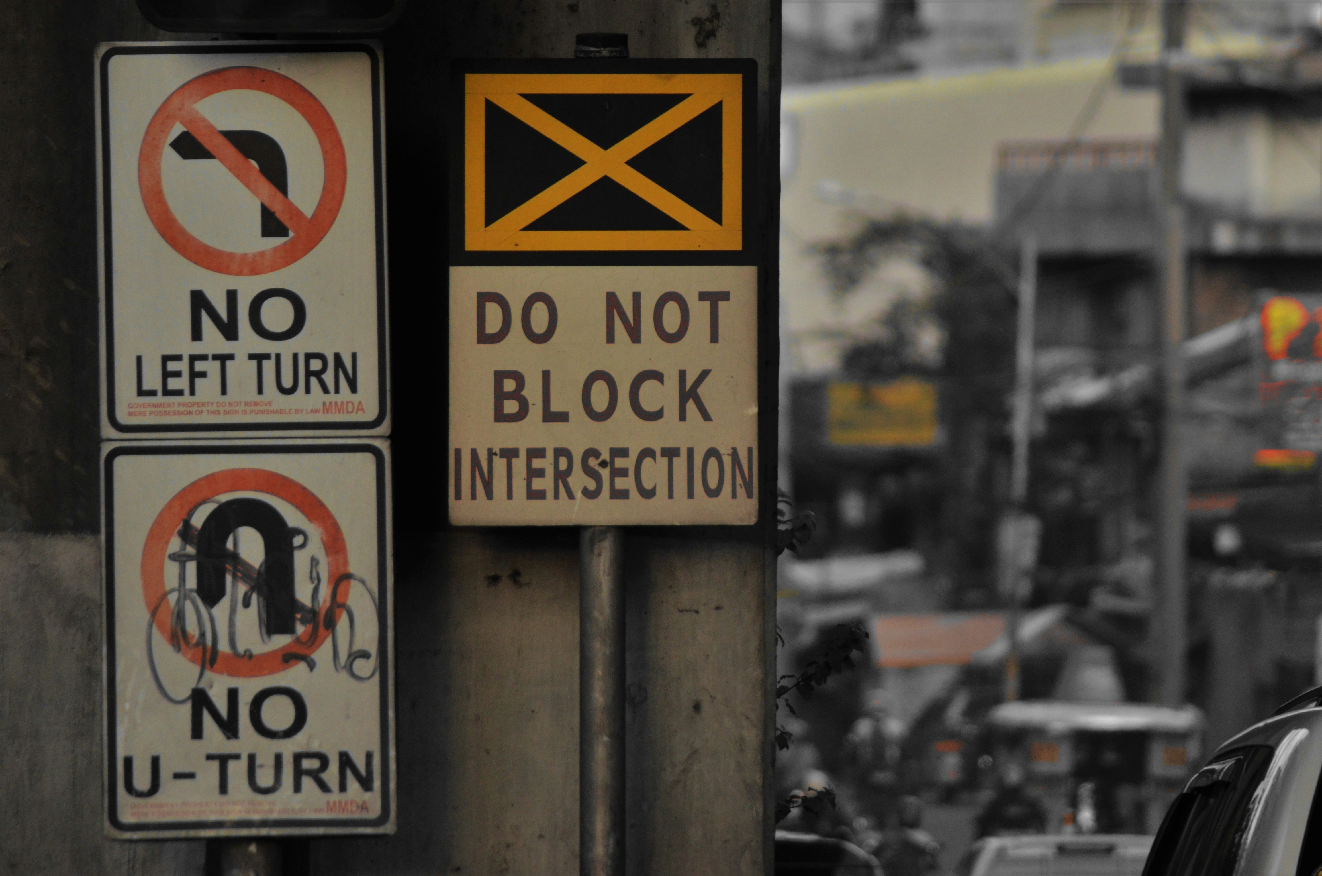 Traffic signs warn against left turns and U-turns at a busy city intersection.