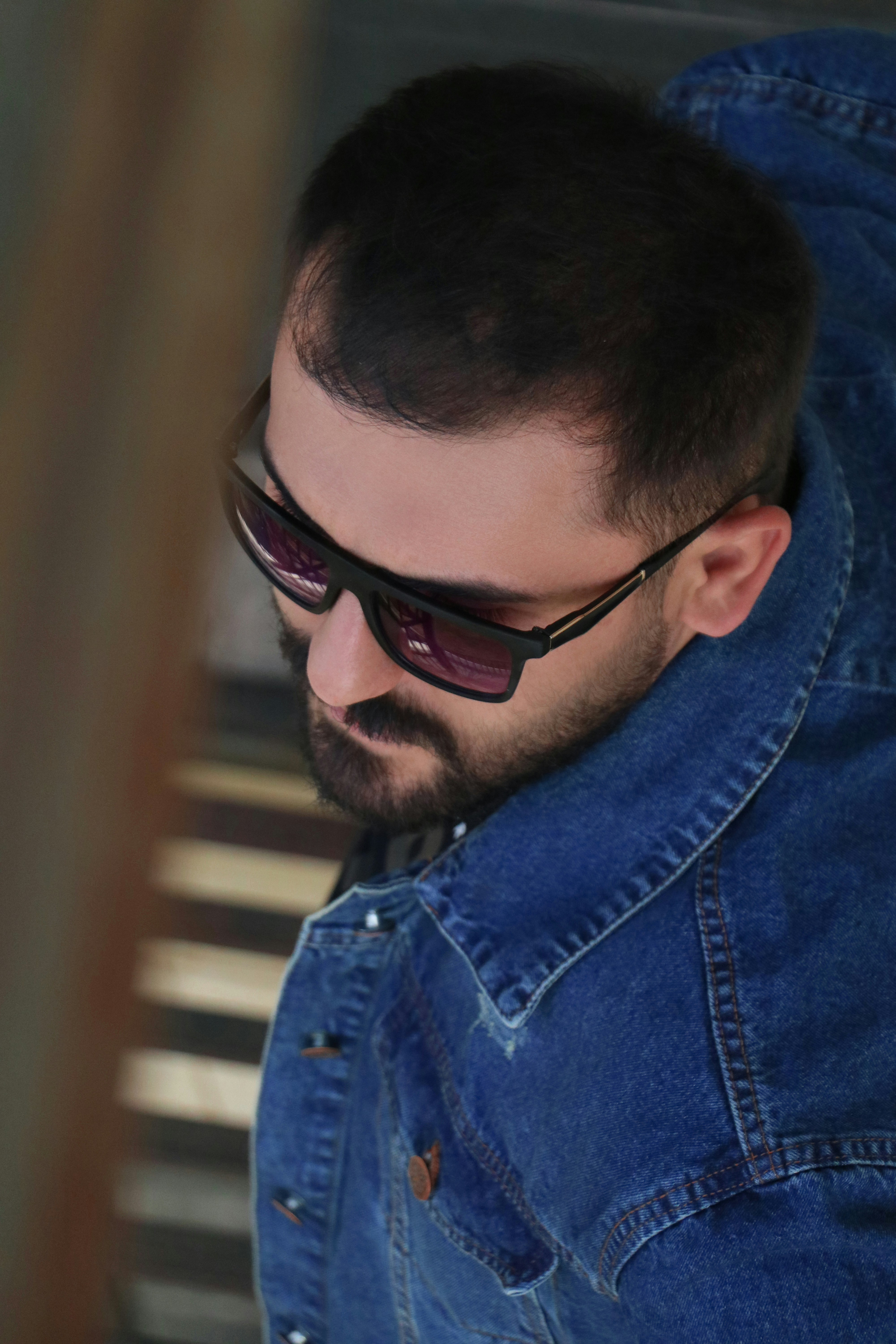 Homme en veste en jean bleue portant des lunettes de soleil noires ...
