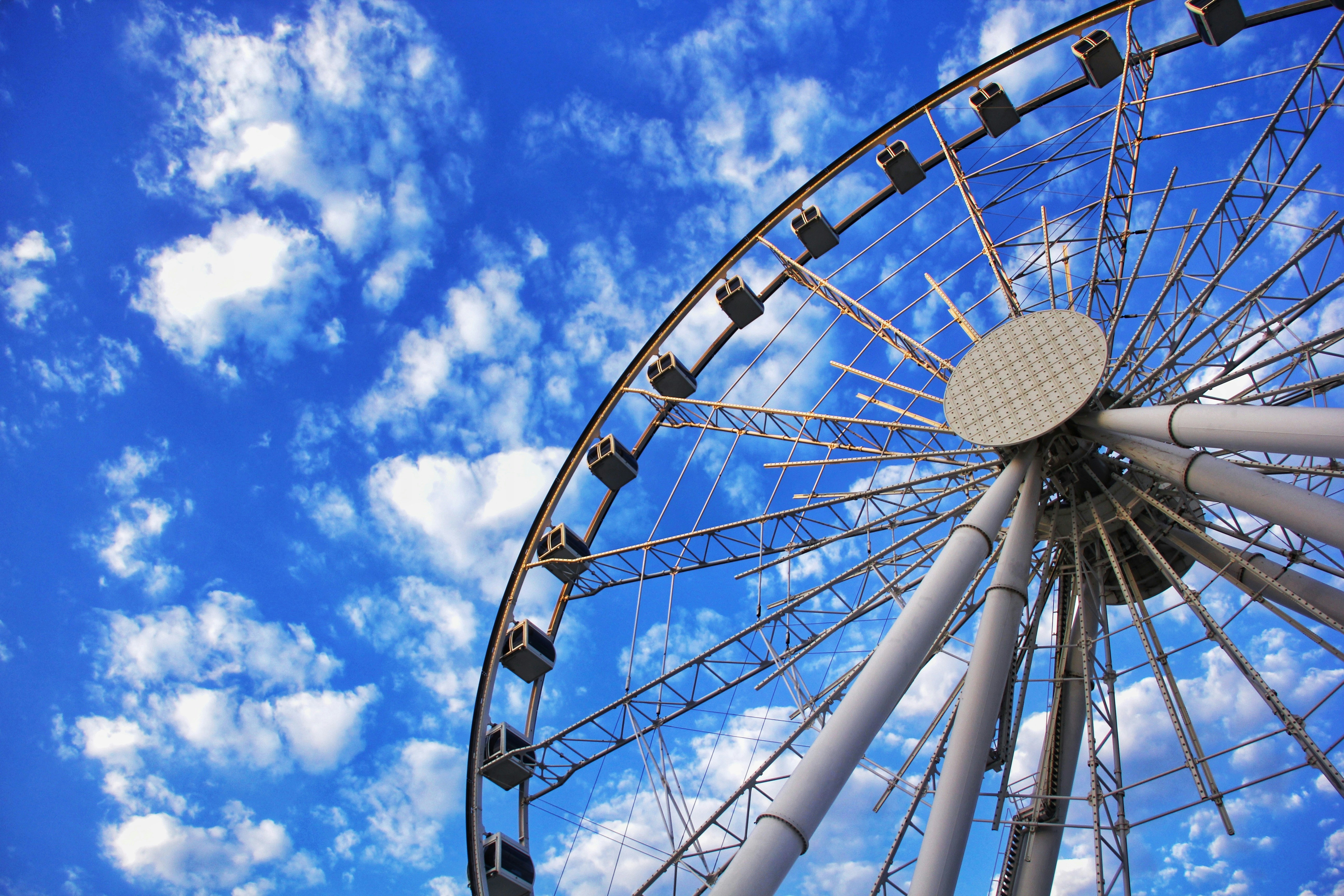 Ferris wheel towering against a vibrant blue sky dotted with clouds.
