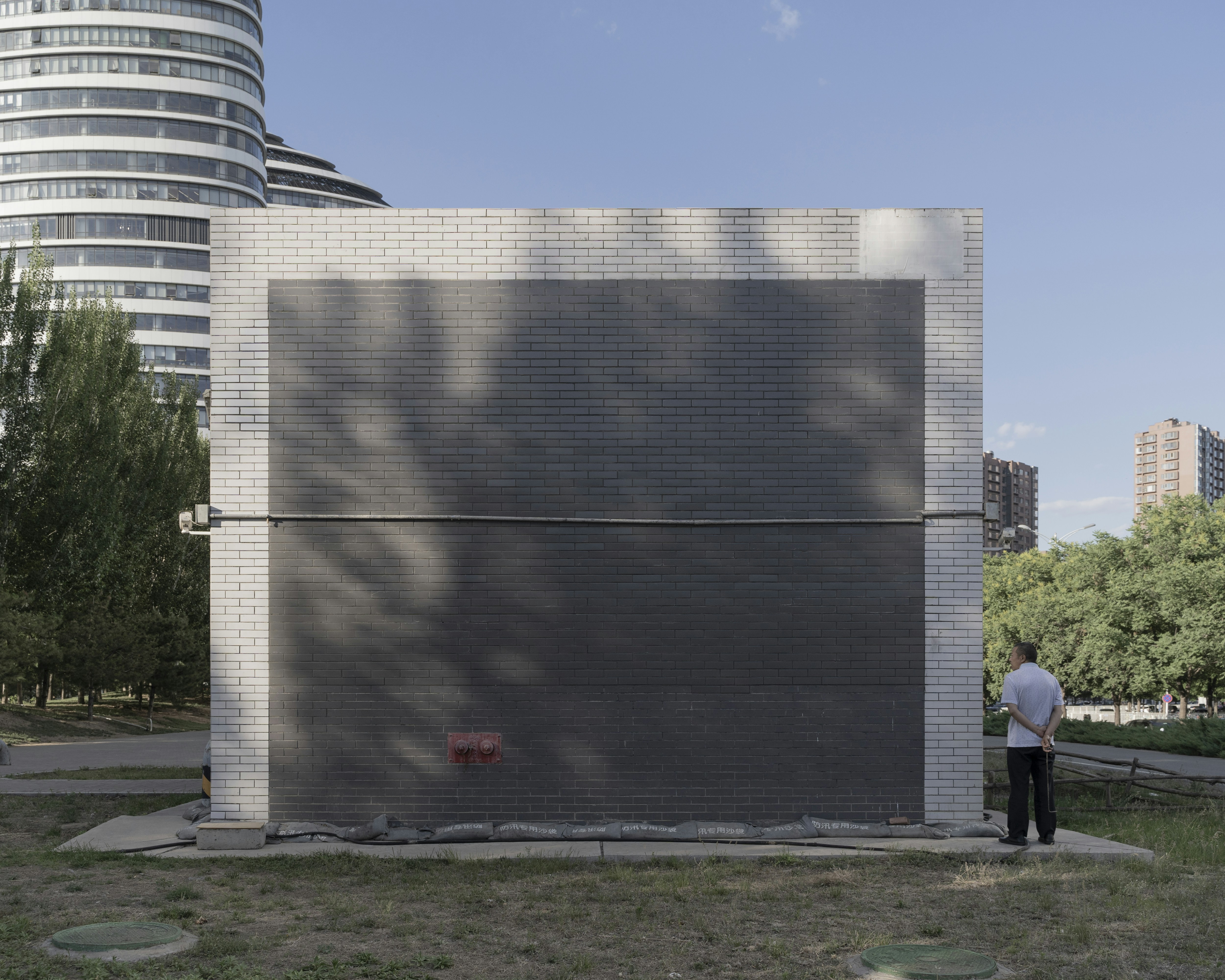 The Silent Proscenium: A Monolithic Brick Panel Amid a City Park