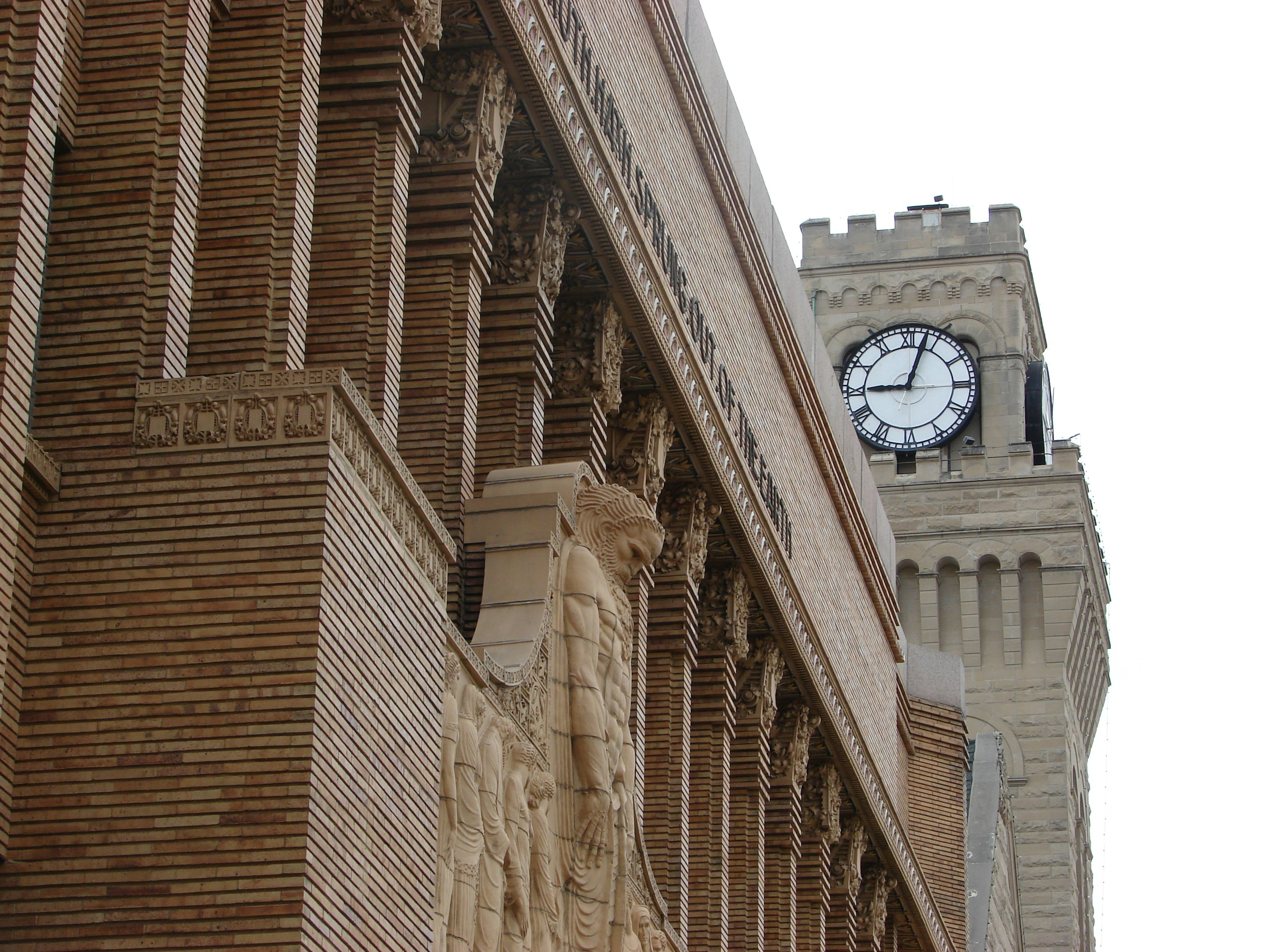 Brick clock tower and adjacent colonnade captured from a low angle.