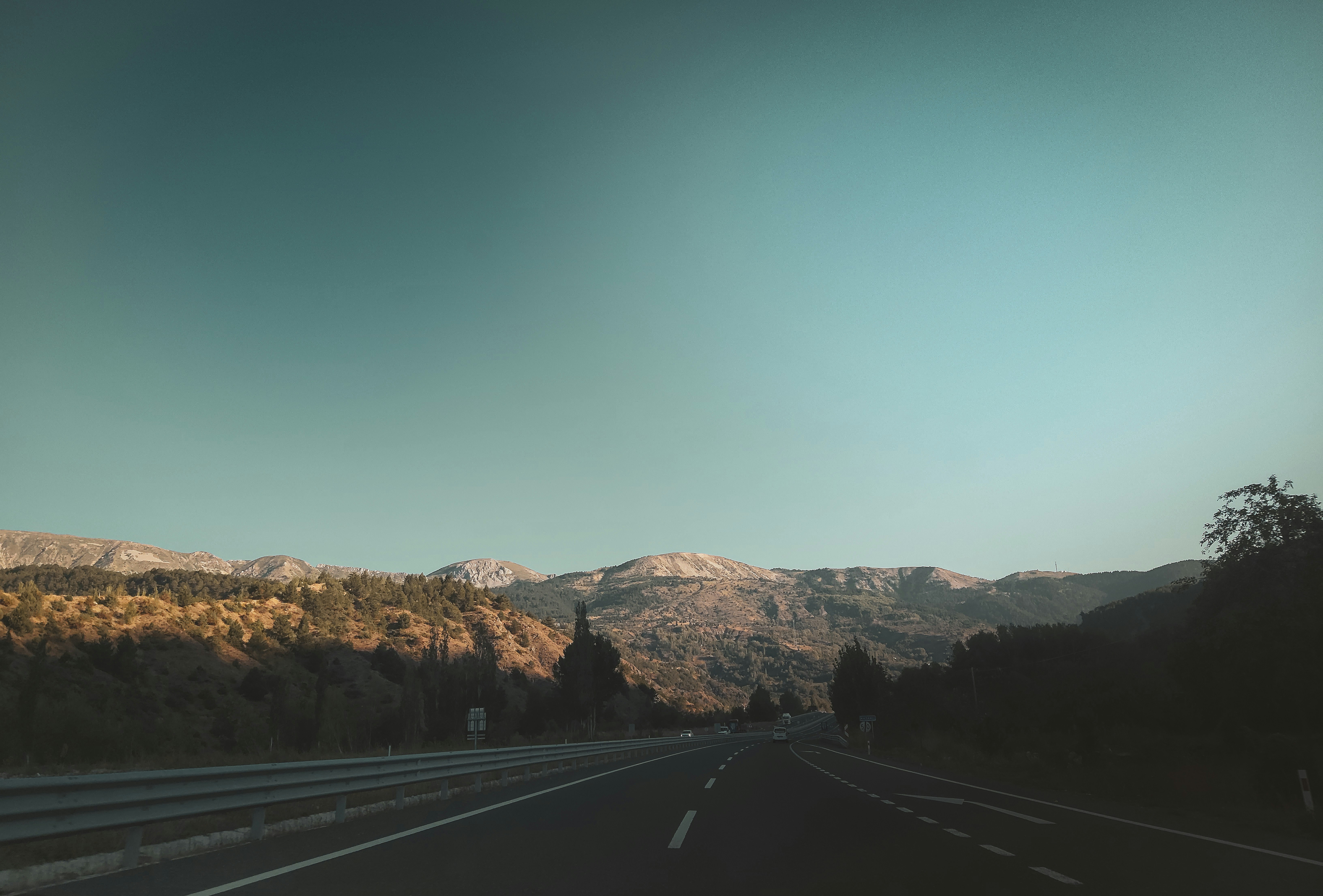 Winding road leads towards distant mountains under a clear sky, showcasing the beauty of nature's tranquility.