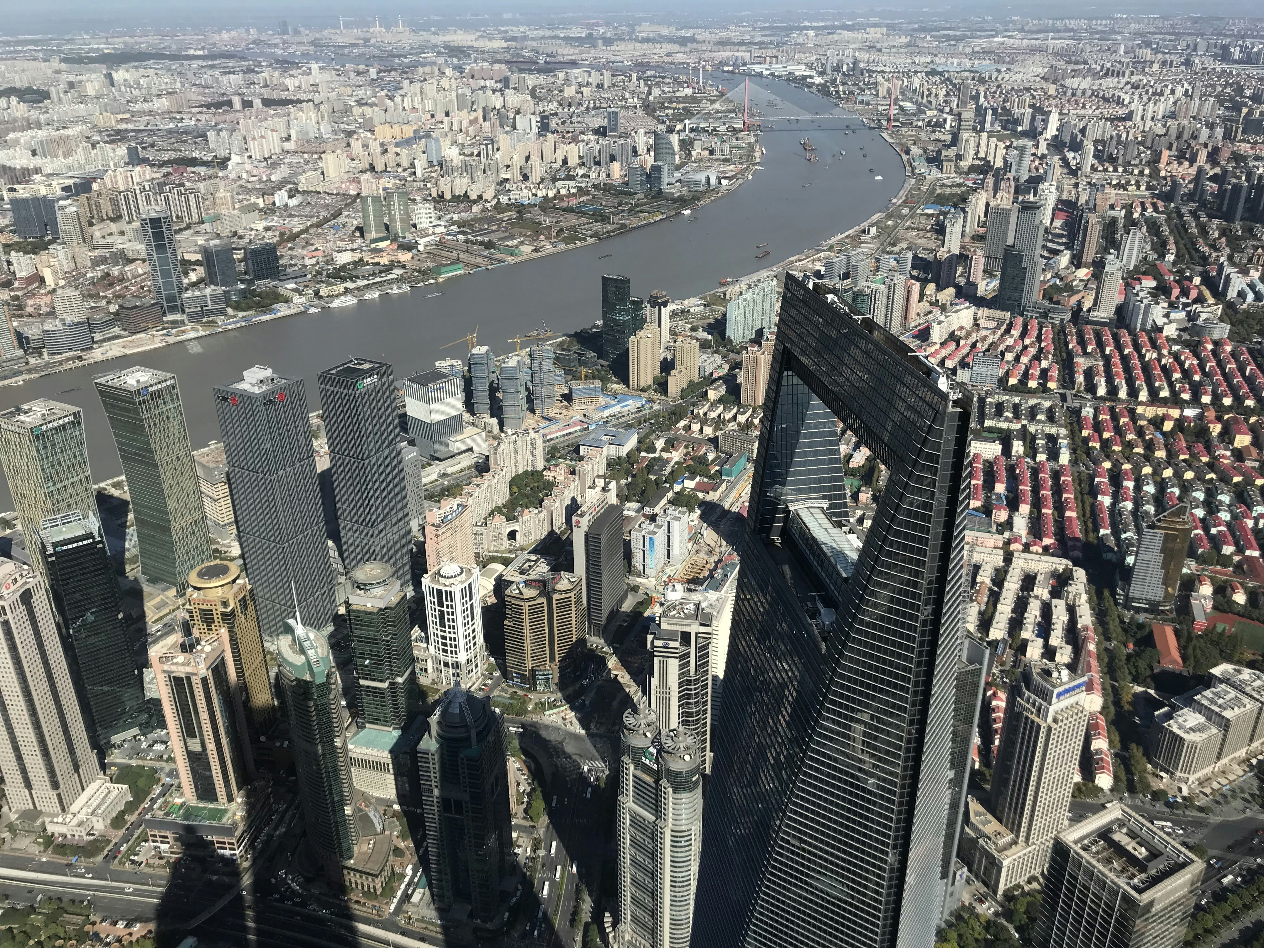 Aerial view of Shanghai showcasing a blend of modern skyscrapers and the winding Huangpu River. The intricate city layout reveals a dynamic urban landscape.
