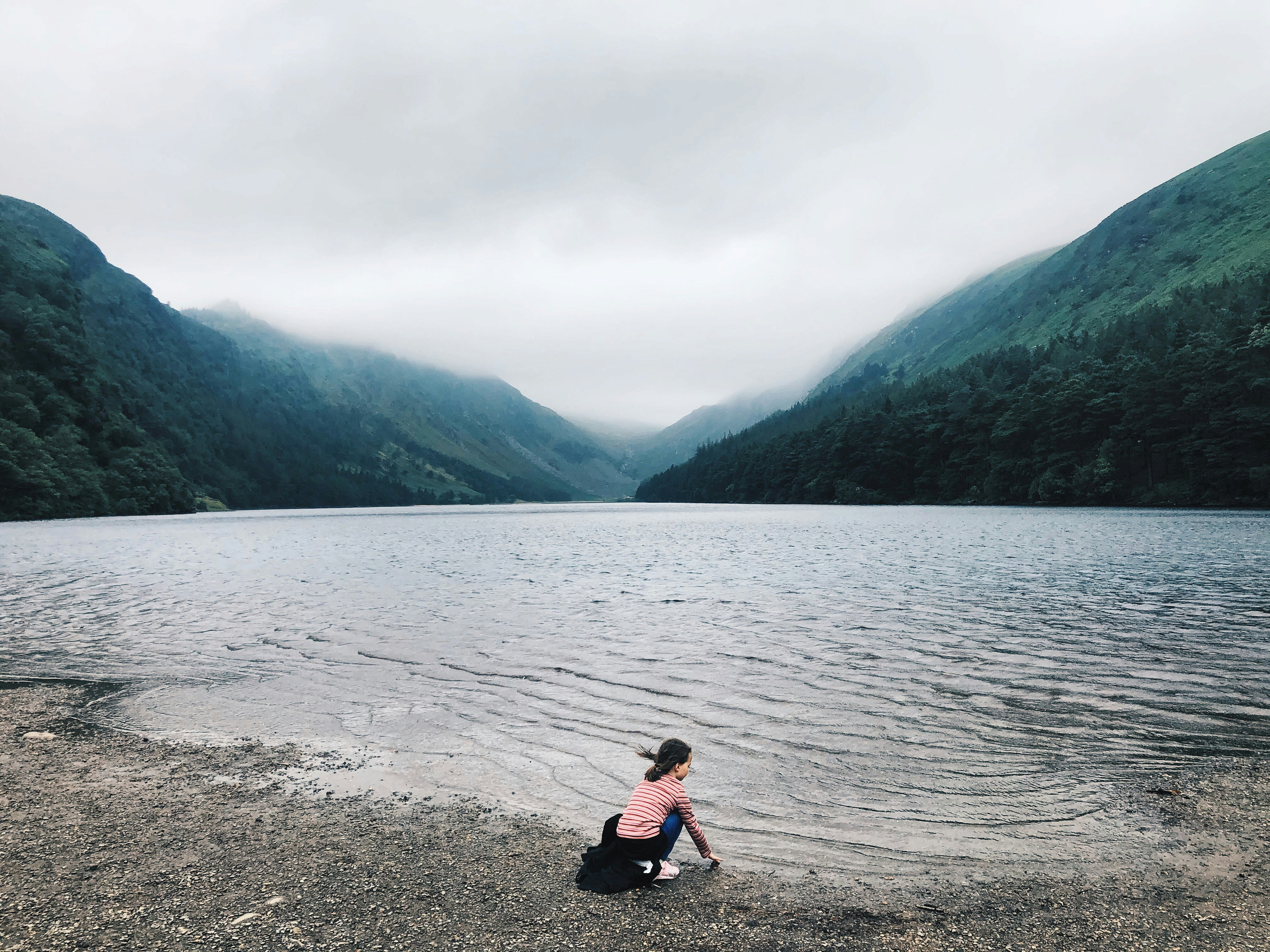 Edge of the Quiet Lake: a lone figure at the valley's shore under misty peaks