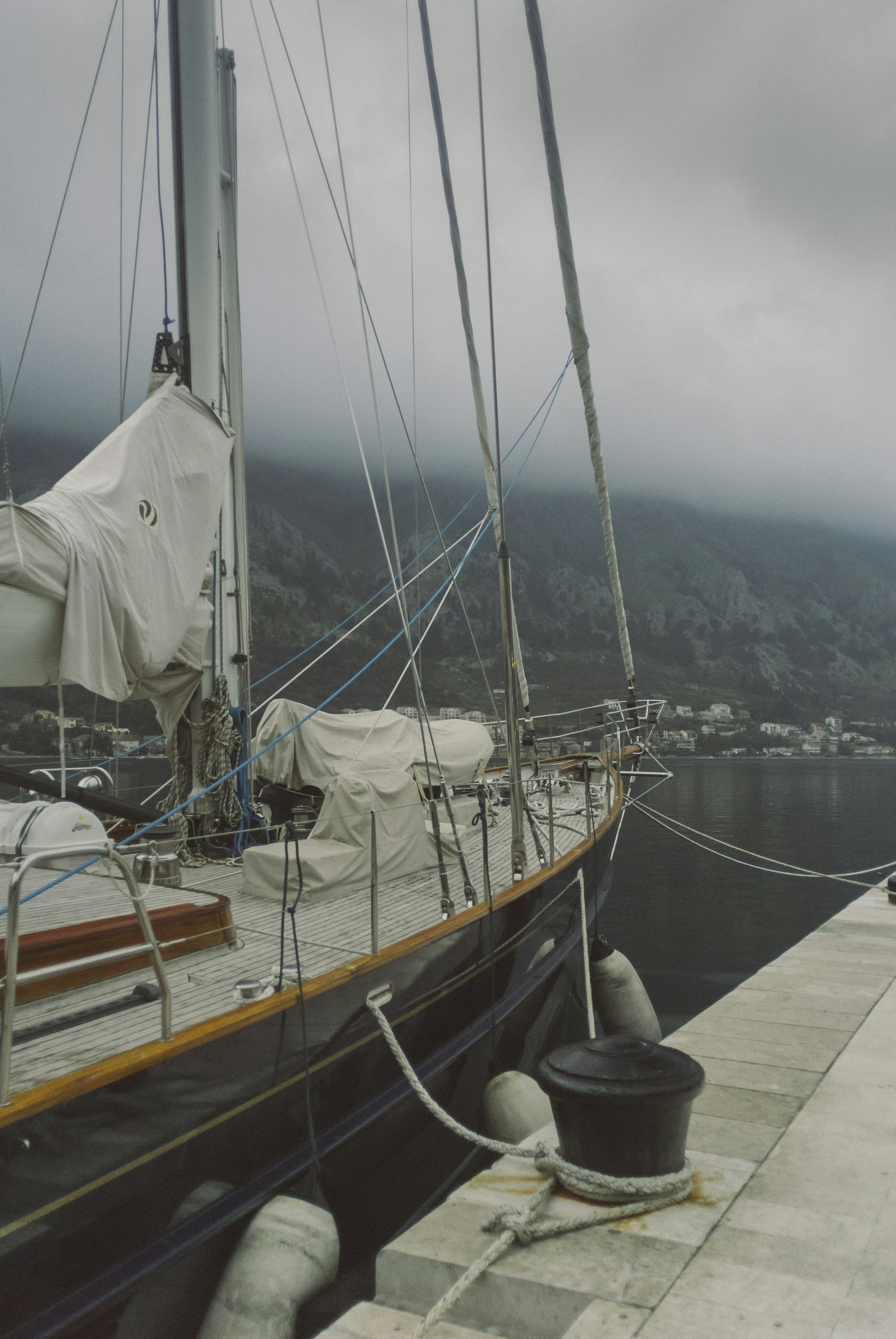 Rigging in a Quiet Fjord: A Docked Sailboat Under a Cloudy Sky
