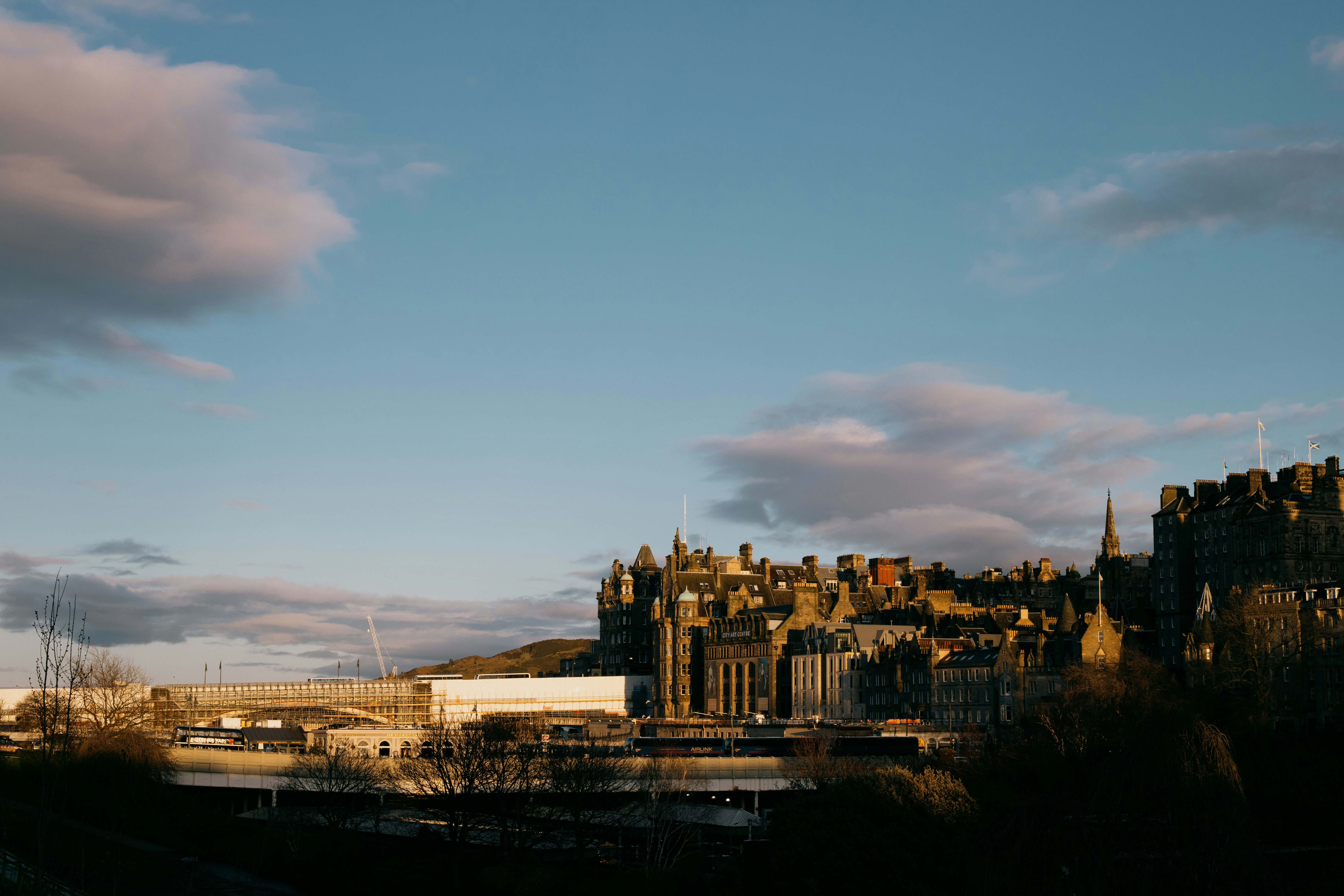 Historic buildings of Edinburgh silhouetted against a twilight sky with soft clouds. The scene captures the city's architectural beauty at dusk.