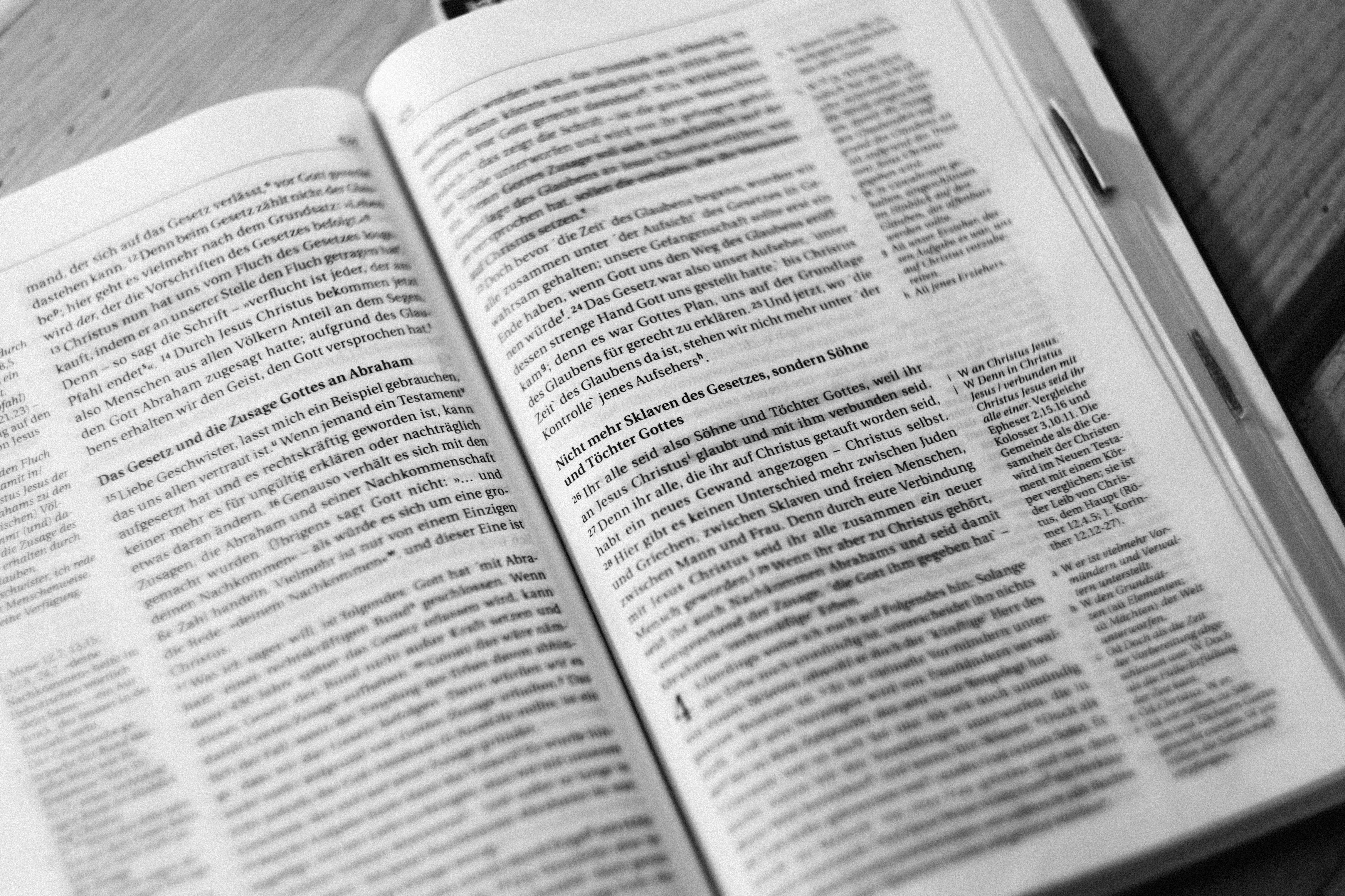 Open book with text in black and white, placed on a wooden surface.