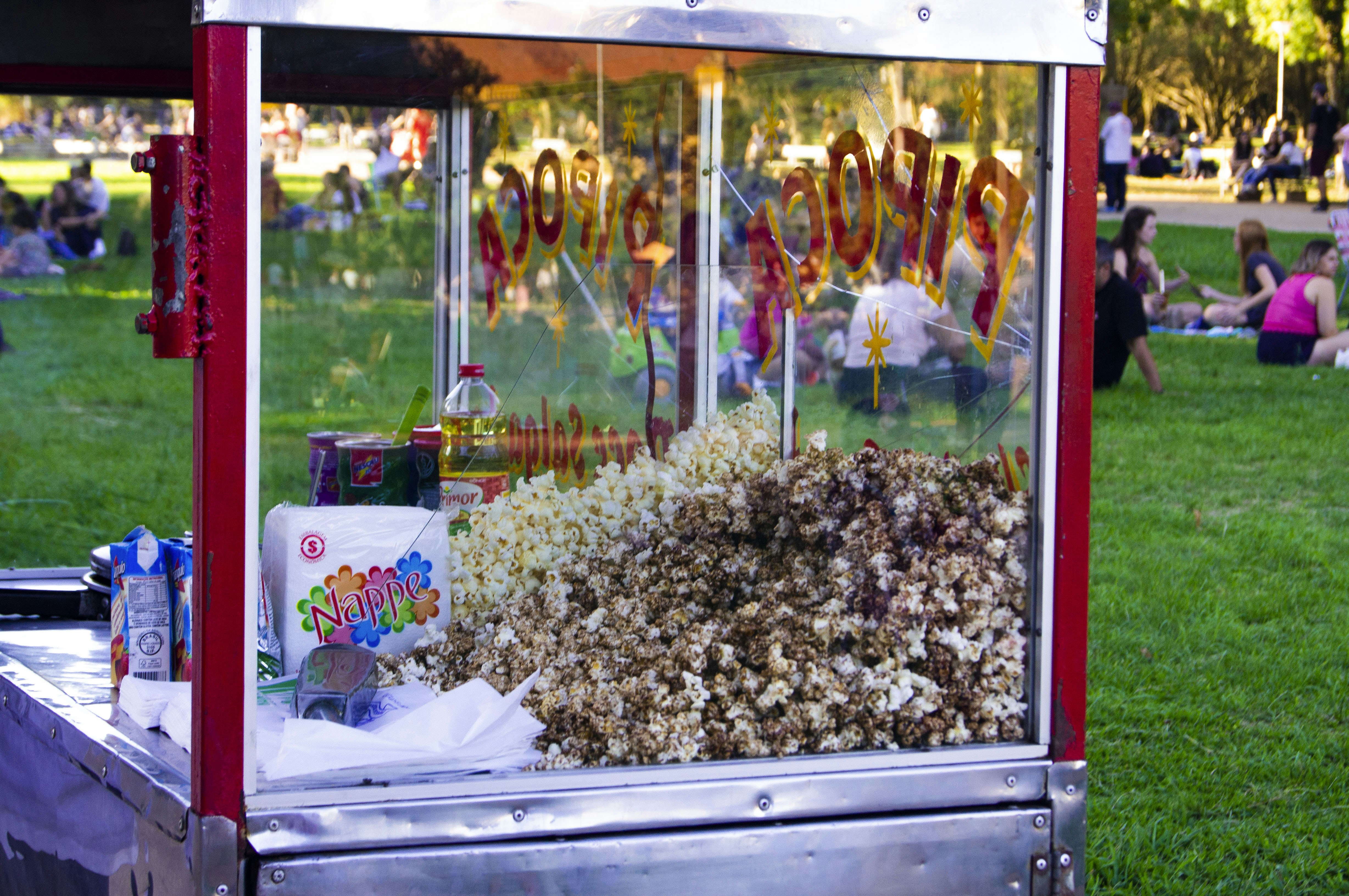 Popcorn cart brimming with fresh popcorn in a lively park setting.