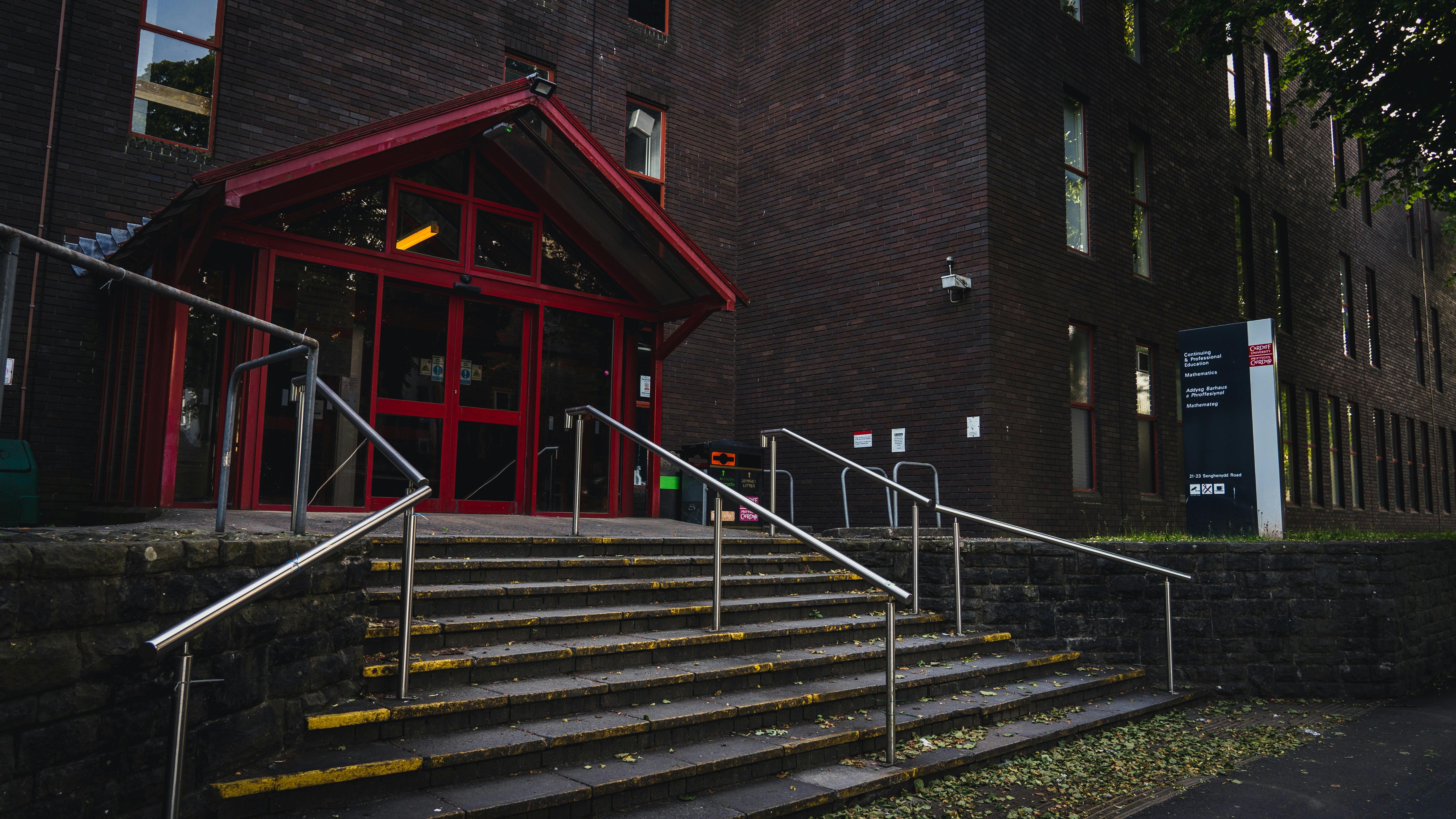 Red Door Threshold: Stairs to a brick campus entrance