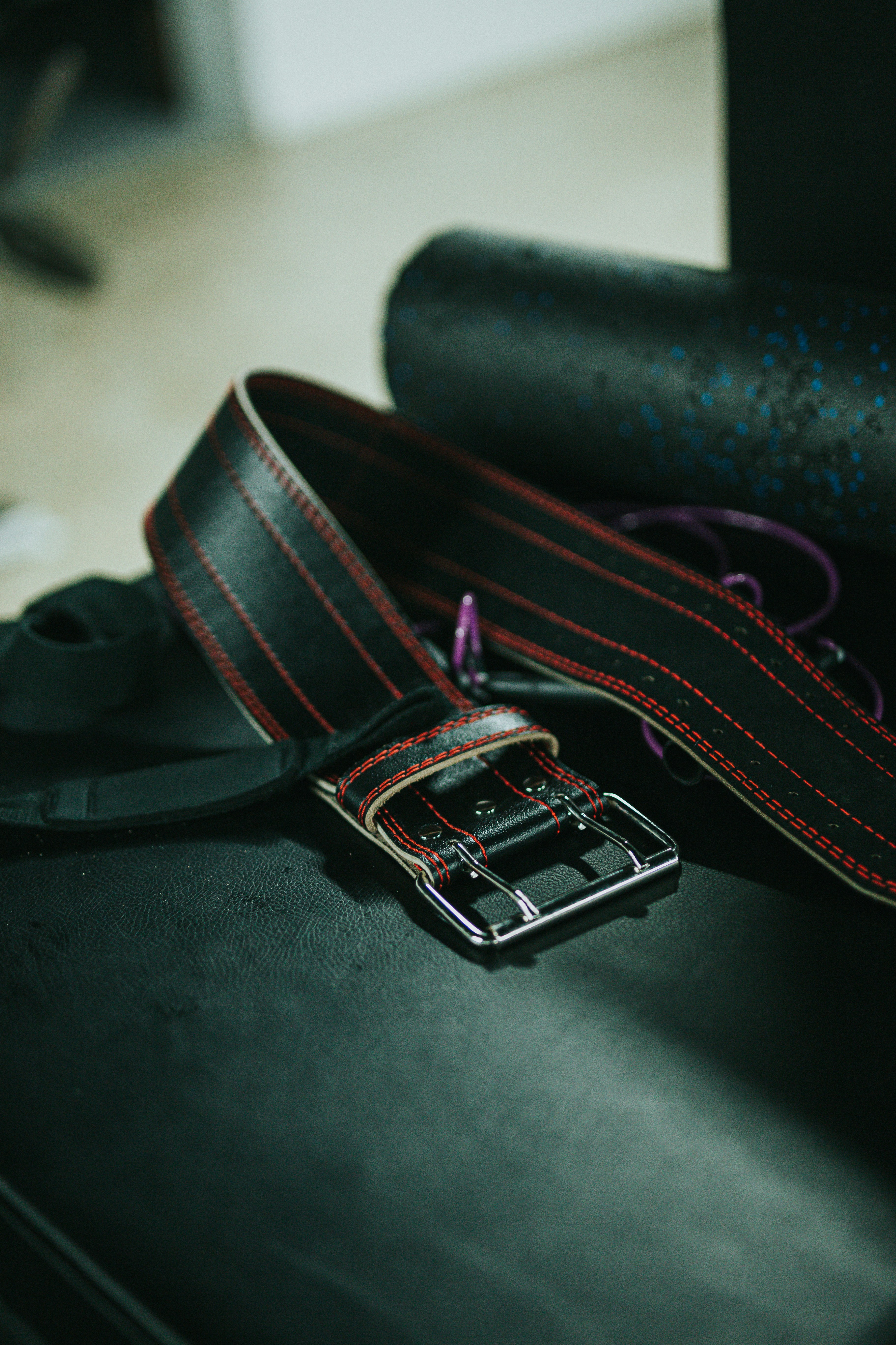 Close-Up of Red-Stitched Leather Belt with Polished Buckle on a Matte Surface