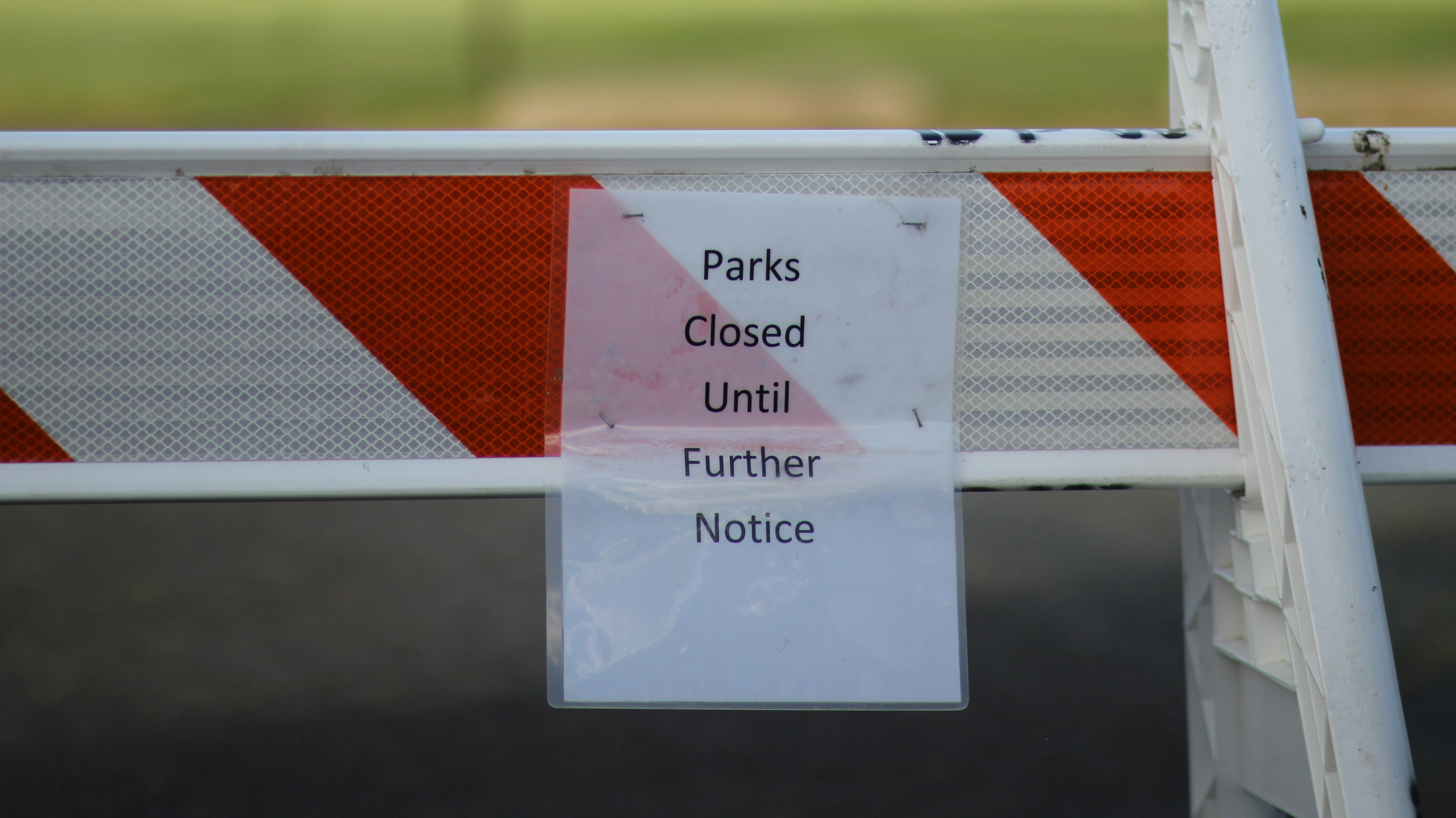 Barrier of Quiet: Parks Closed Sign on a Striped Gate