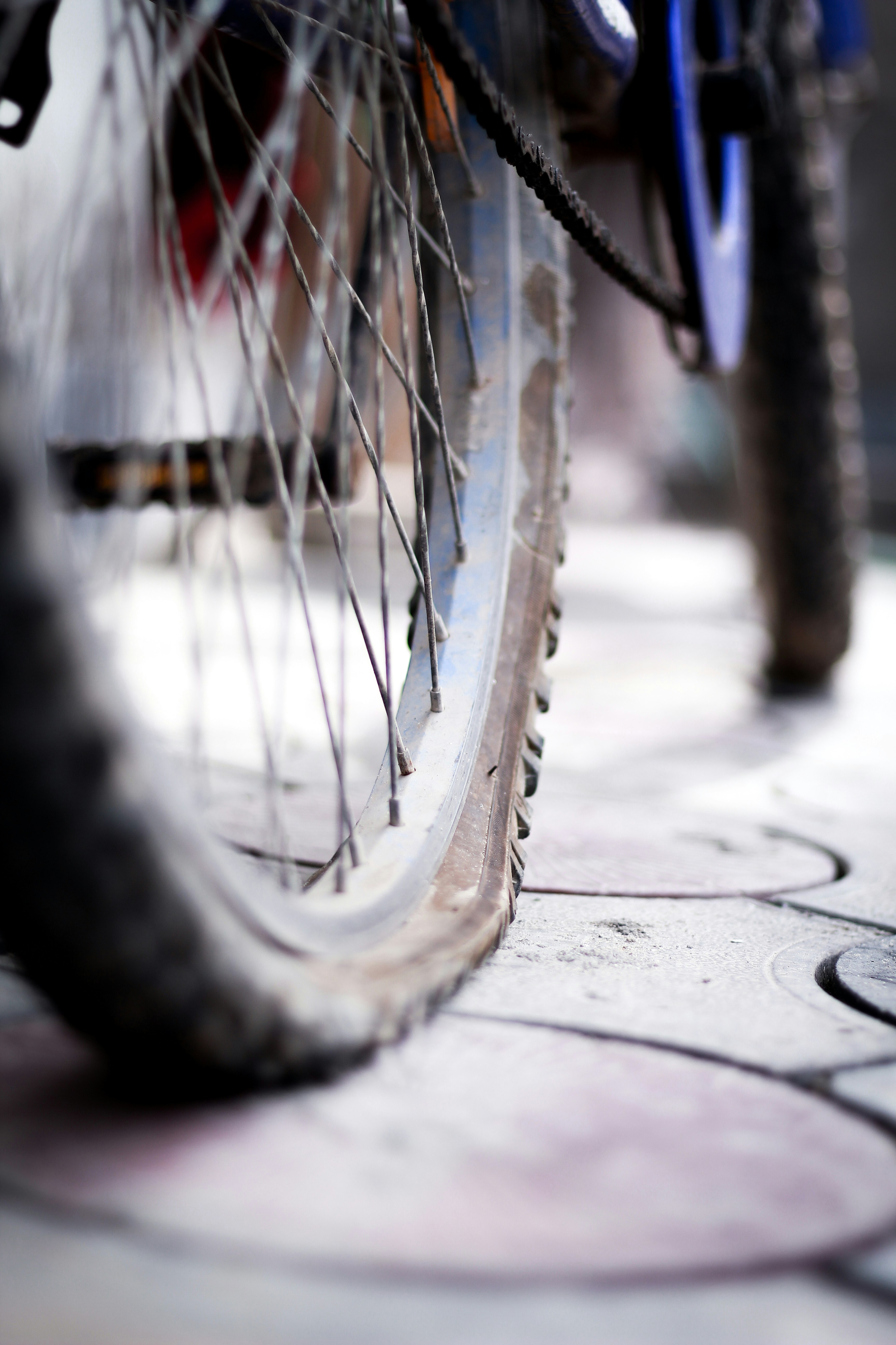 Spokes in Focus, Pavement in Blur: Mud-Splashed Bicycle Wheel Close-Up