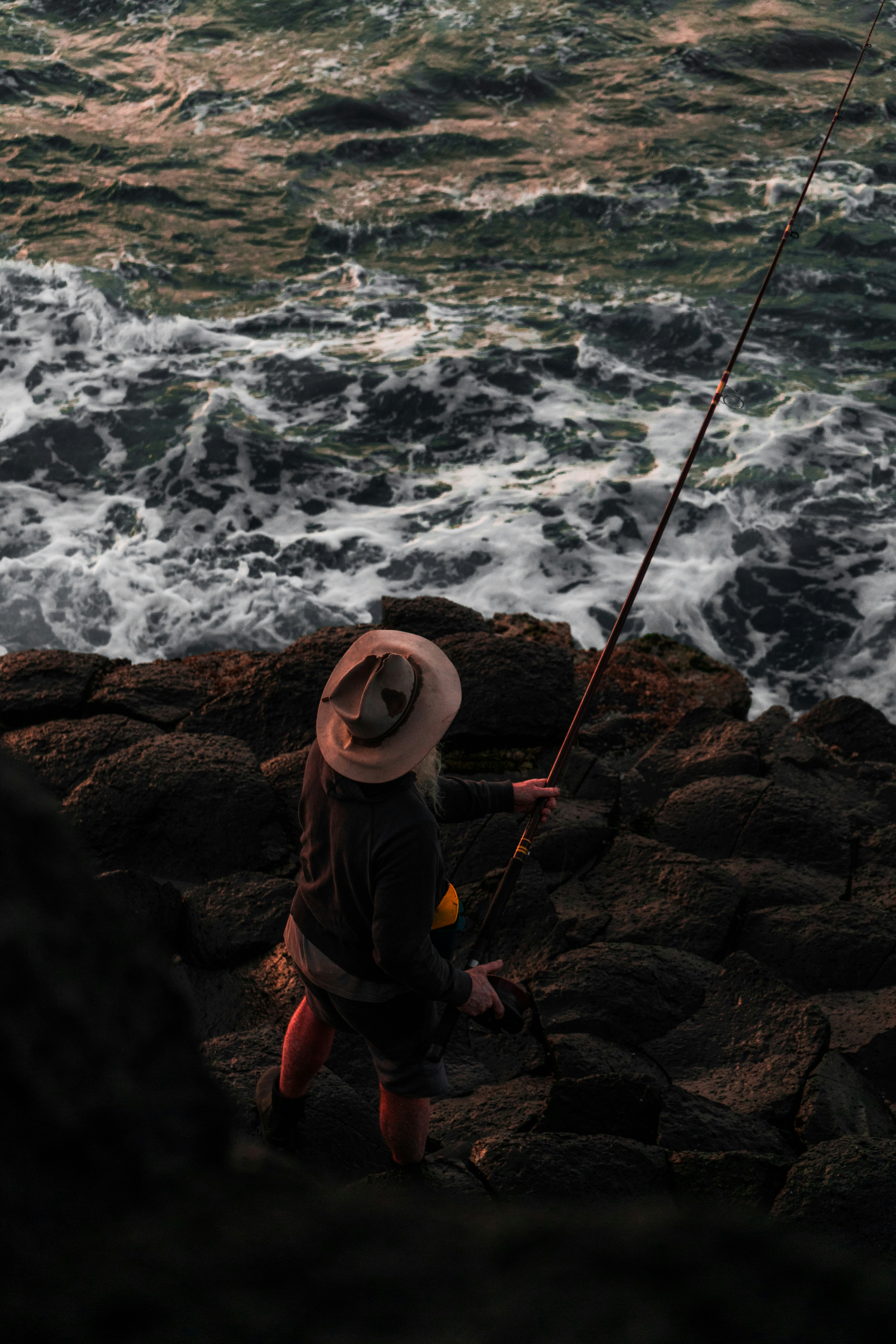 Line Cast on the Edge: A Seaside Angler Braving the Jagged Shore
